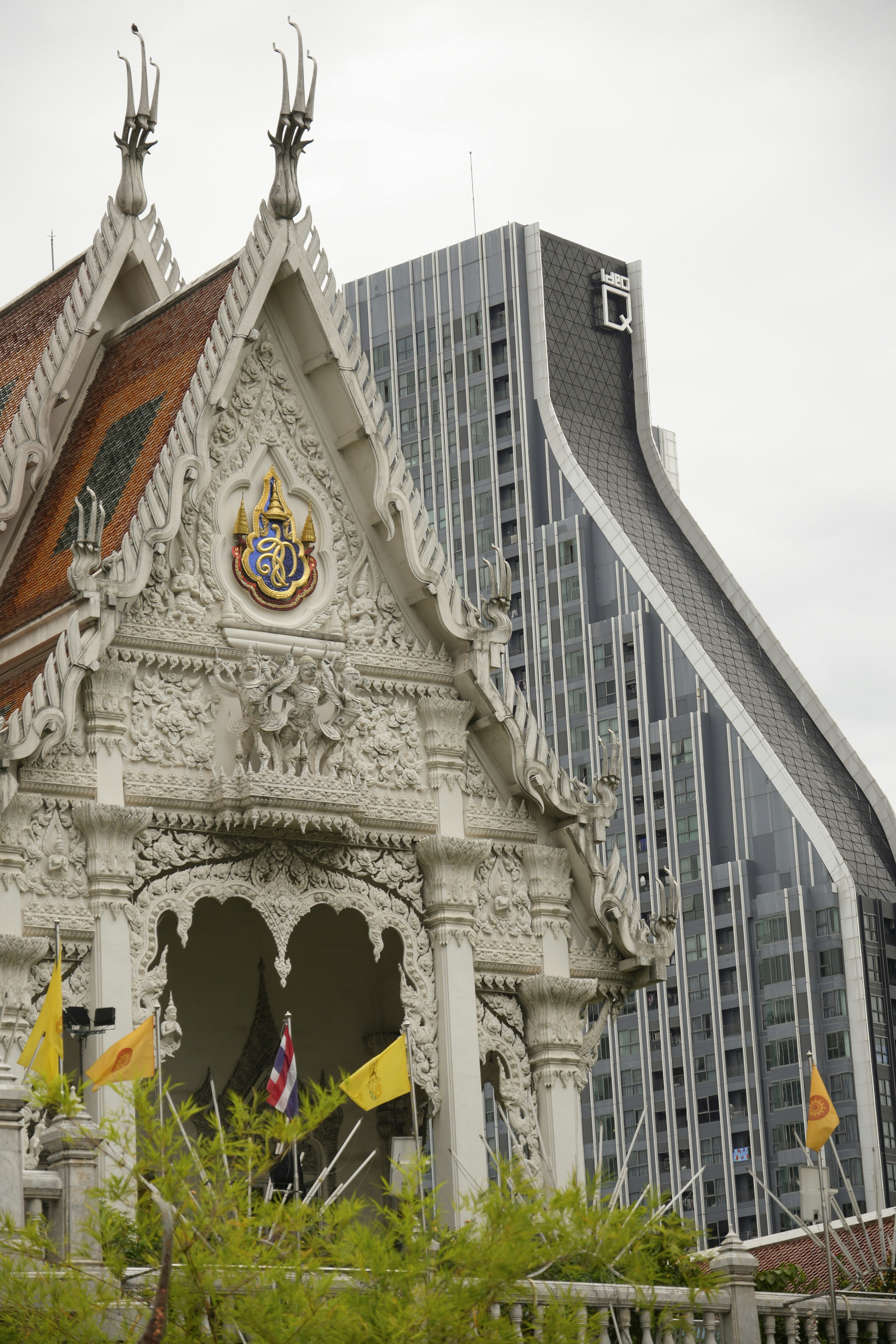 An ornate temple stands beside a modern skyscraper.