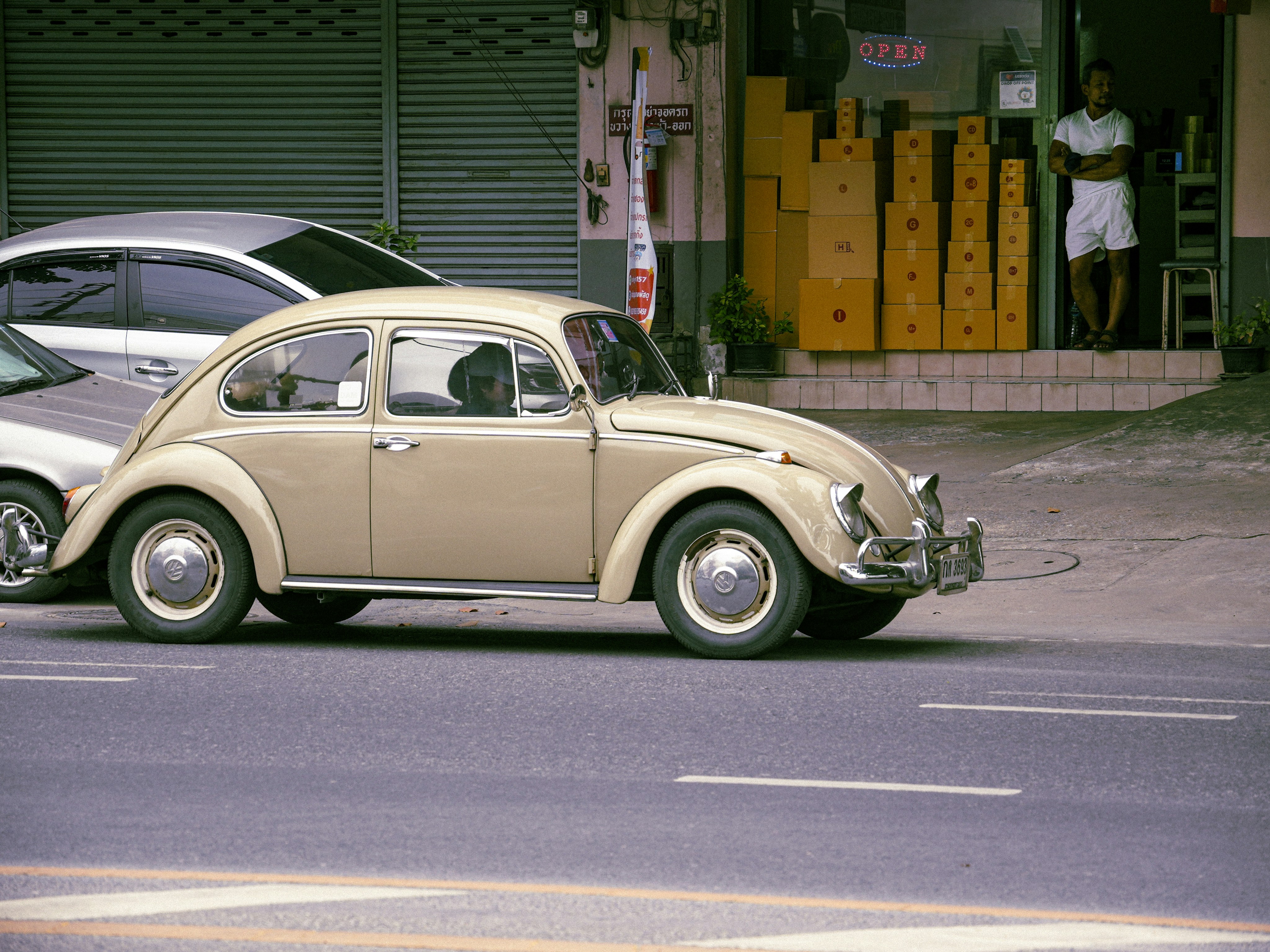 A classic beige volkswagen beetle is parked.
