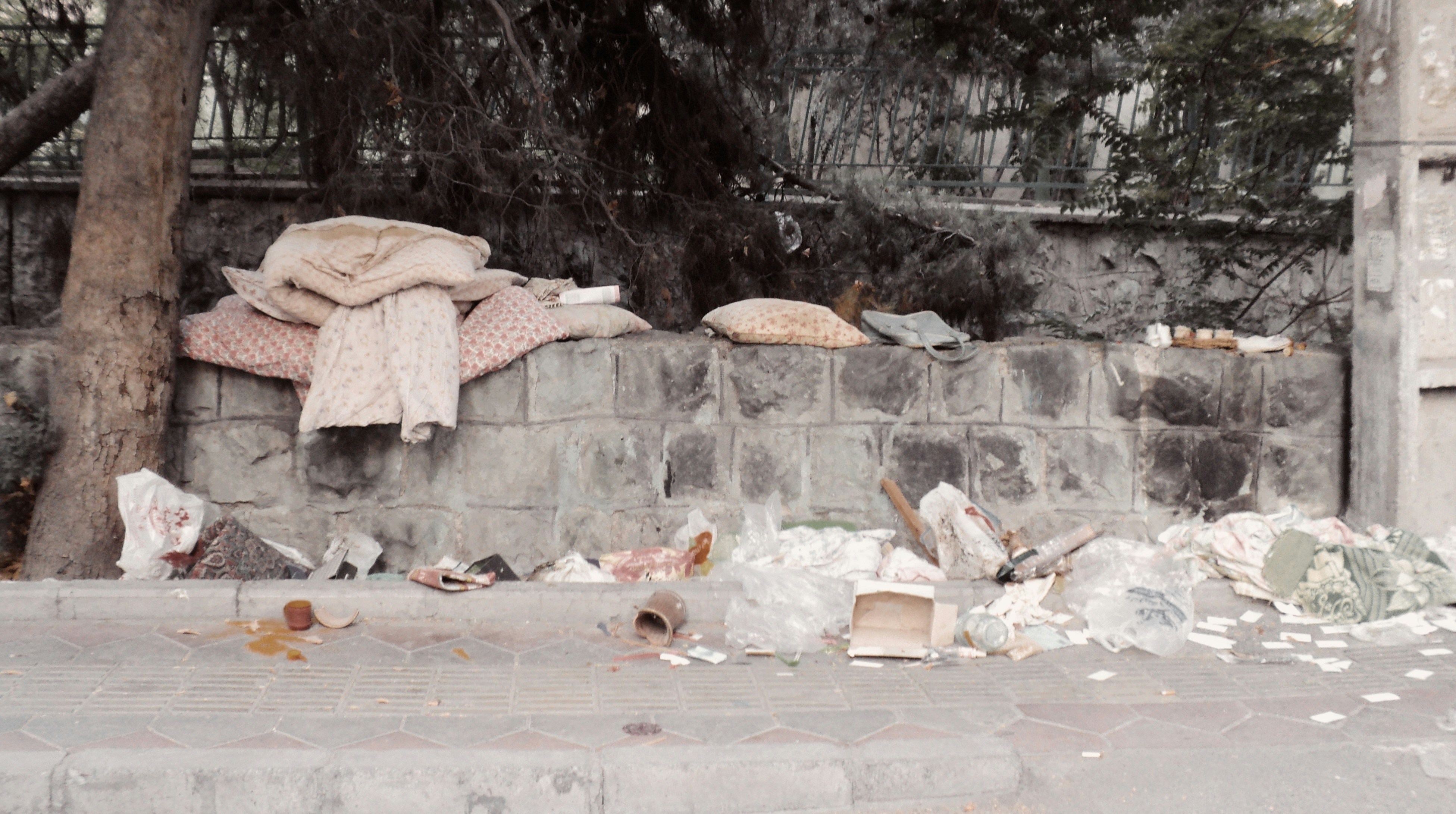 A bedroom without walls. | Homeless person's belongings strewn on the sidewalk.