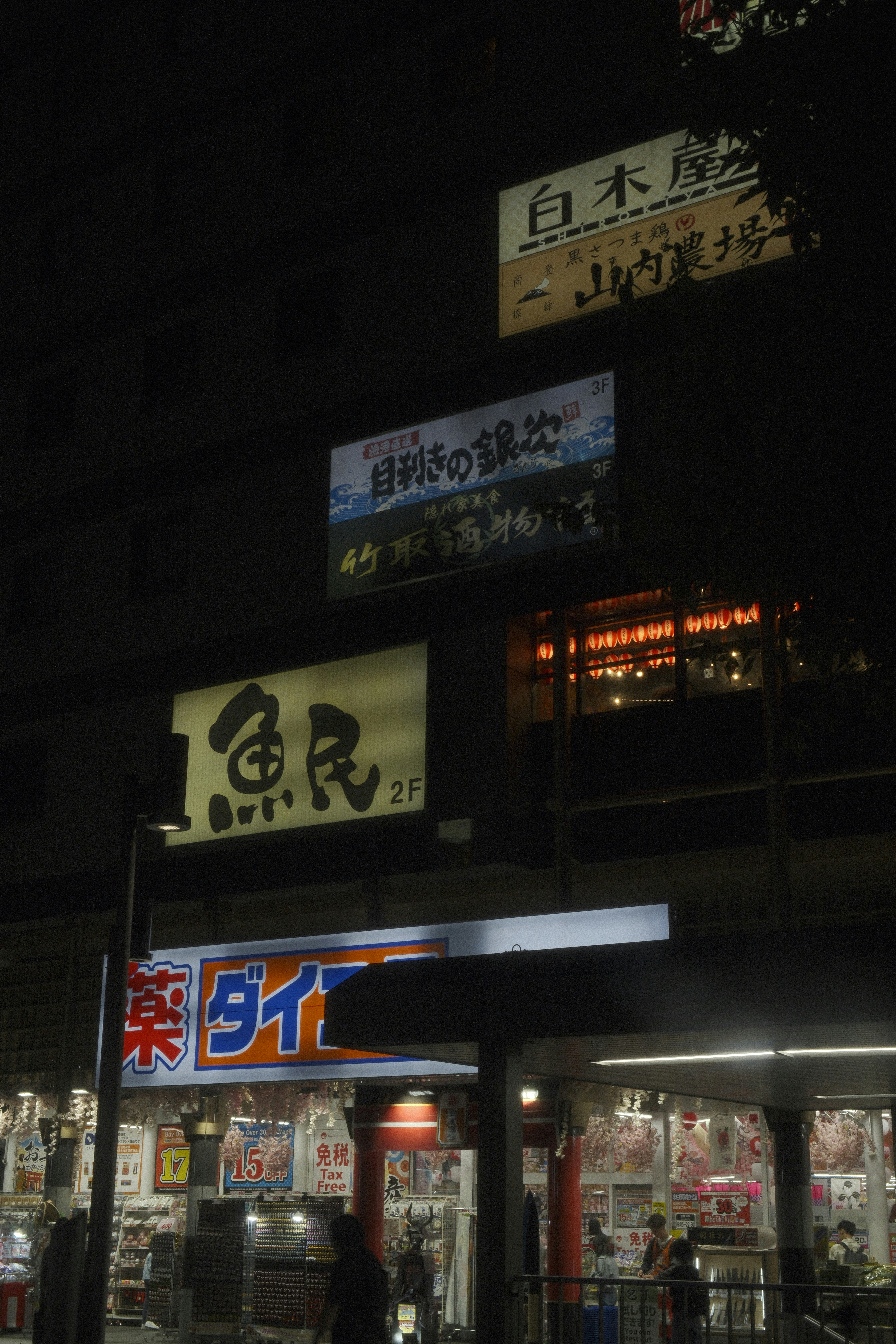 Nighttime in japan featuring lit-up storefronts.