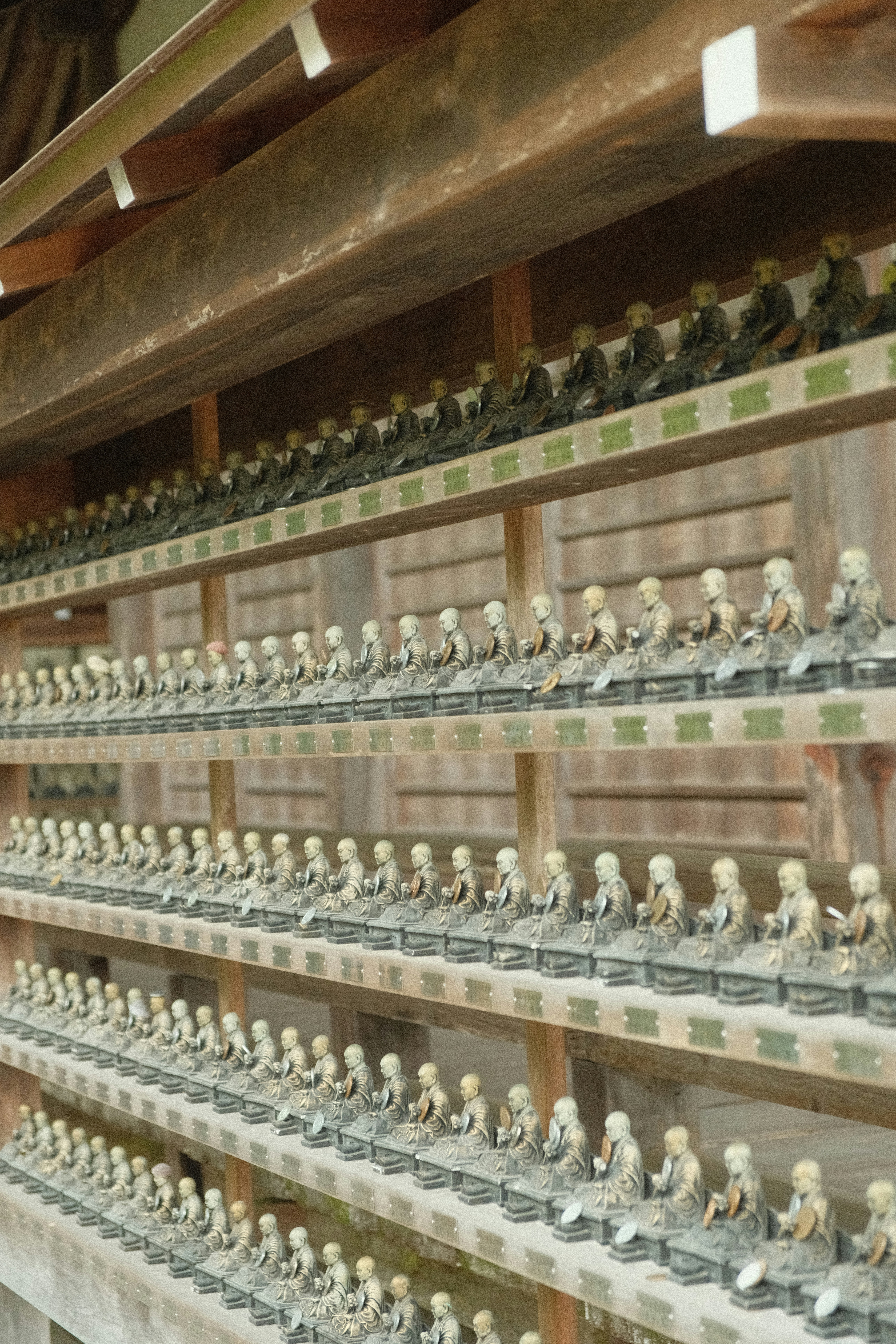 Rows of small buddhas fill wooden shelves.