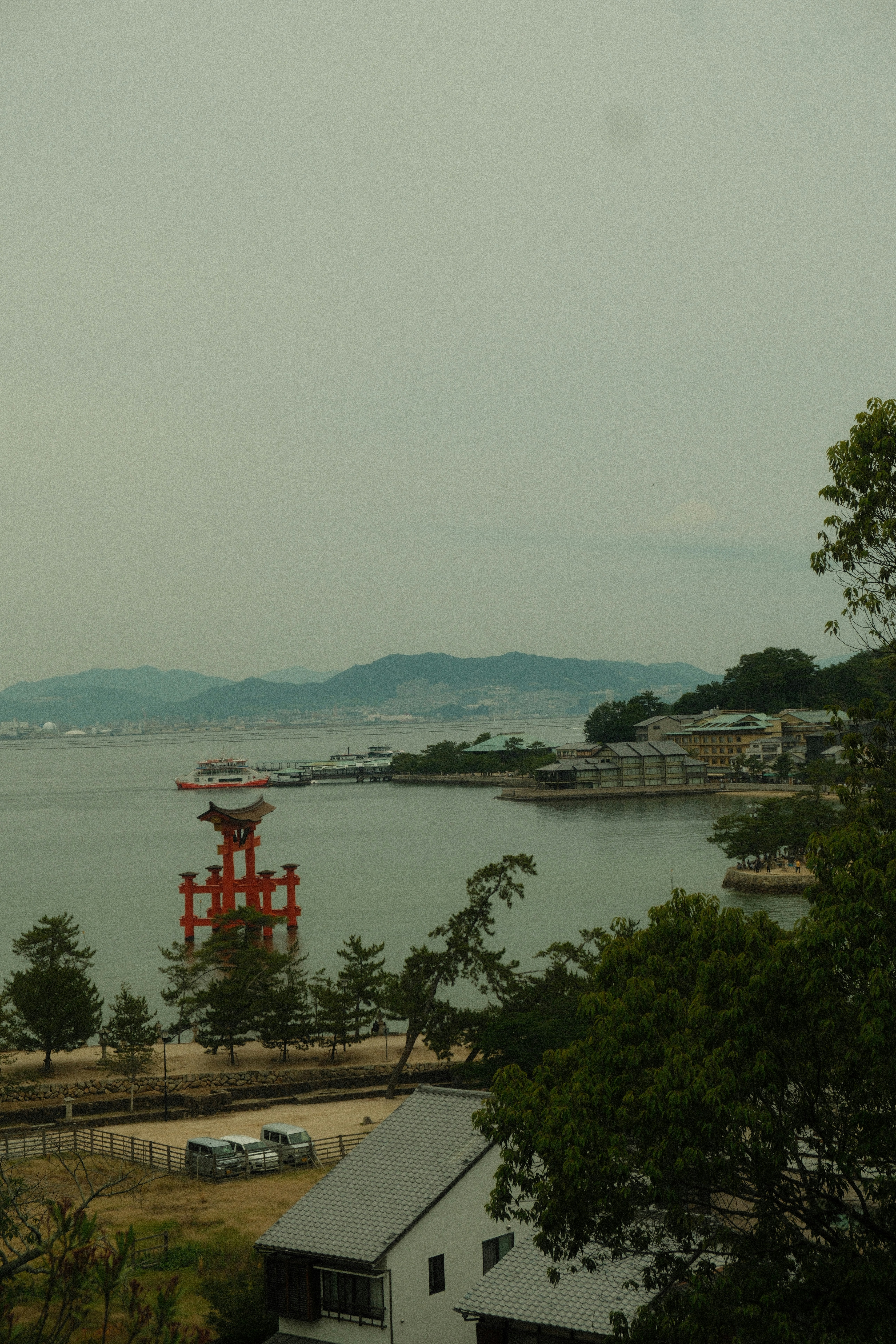 A red torii gate stands in the calm water.