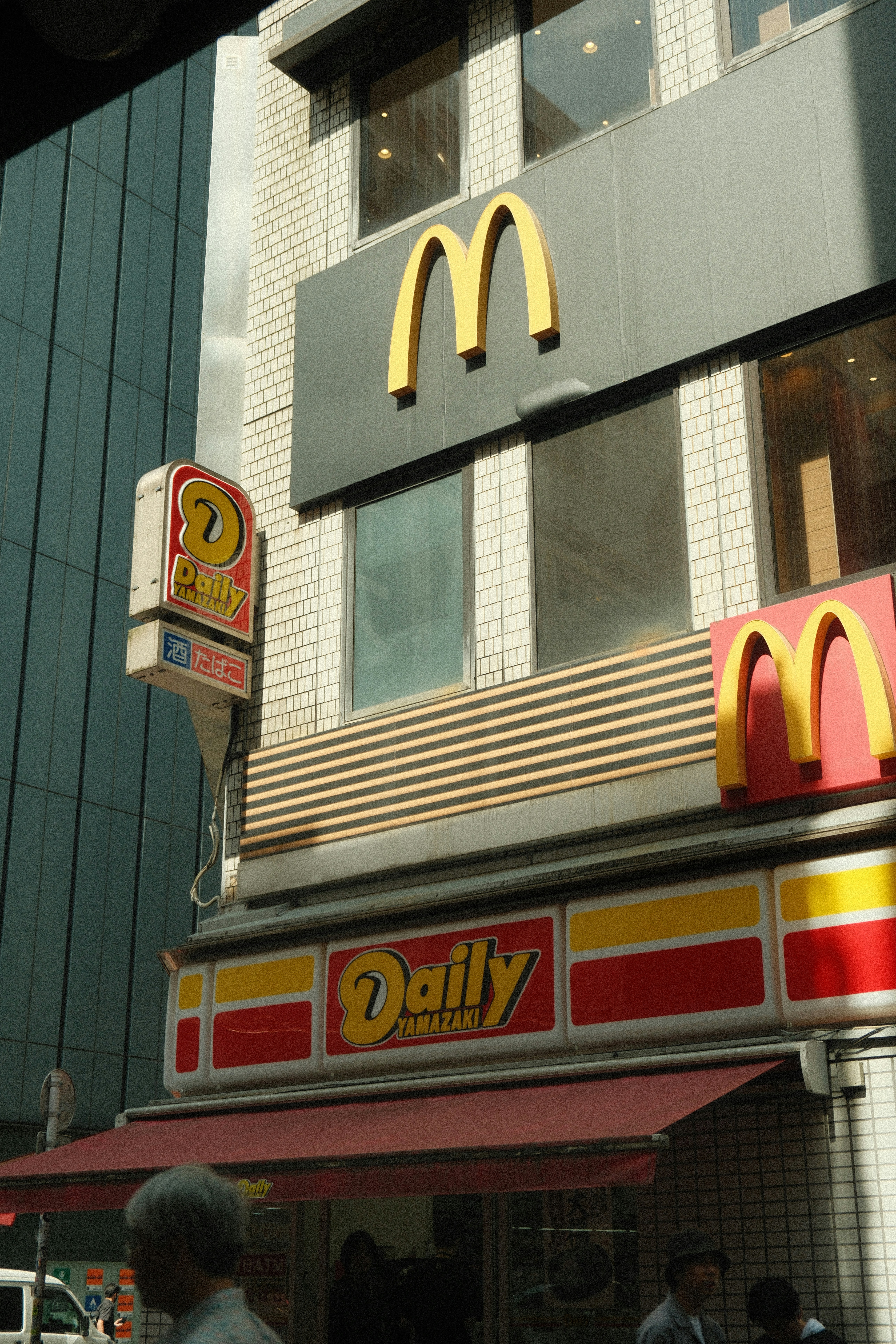 A mcdonald's restaurant is next to a daily store.