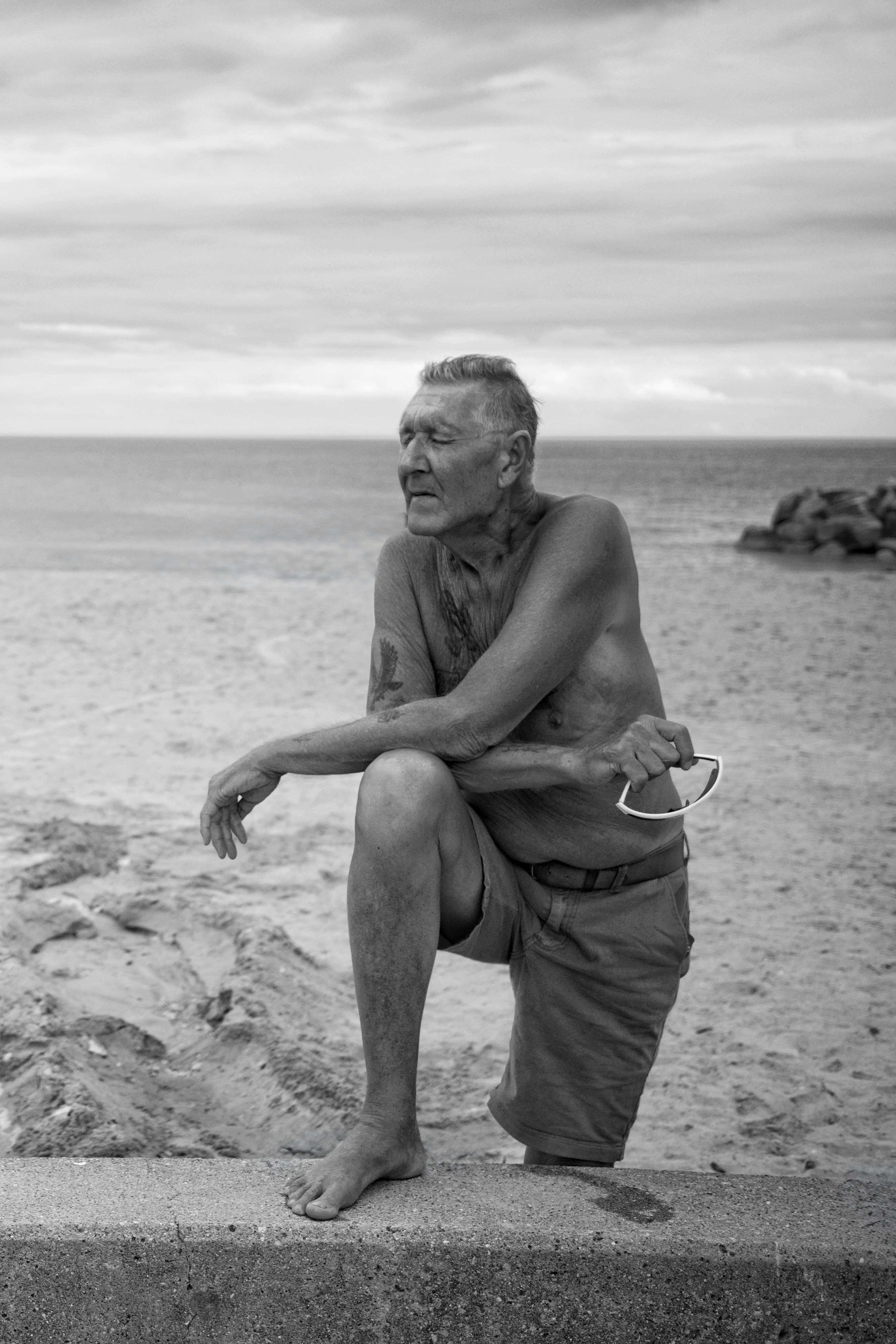 A senior man rests at the beach, thoughtfully.