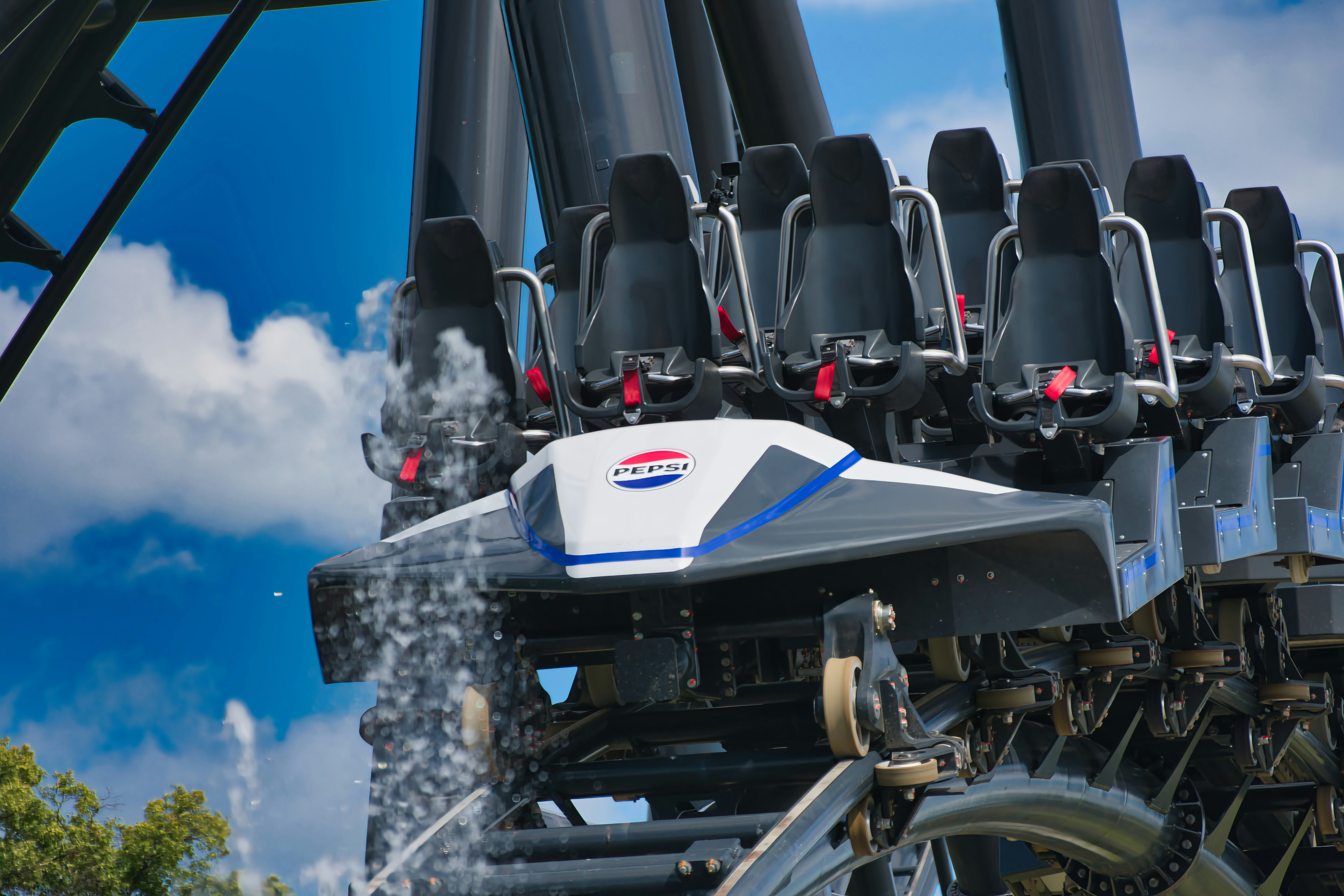 Hyperion — colossal airtime, cosmic ambition. Towering 77 m above Energylandia, this Intamin mega coaster launches riders into a beyond-vertical 82 m drop at 85°, followed by aggressive ejector hills, banked turns, and a powerful twist-and-dive inversion. Blending raw speed with zero-g weightlessness, Hyperion is Europe’s airtime juggernaut. Type: Mega Coaster (Intamin) Opened: 14 July 2018 Height: 77 m Drop: 82 m at 85° Length: 1,450 m Top Speed: 142 km/h Inversions: 1 (Twist & Dive) Duration: ~1:30 min G‑Force: up to 4.8 g Trains: 2 trains with 7 cars (4 riders per row) Theme: Space explora | A rollercoaster car is spraying water.