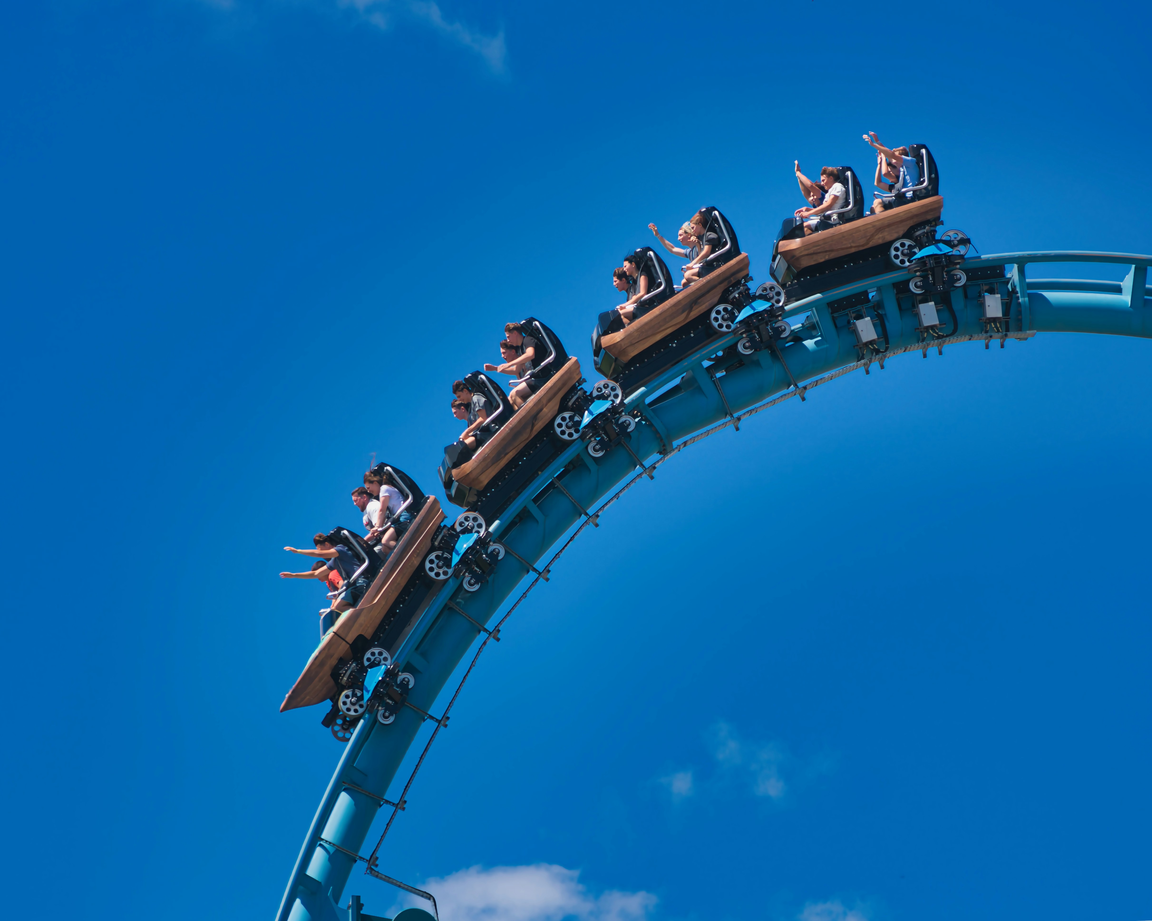 Roller coaster train navigating a steep curve with excited riders enjoying the thrill under a clear blue sky.