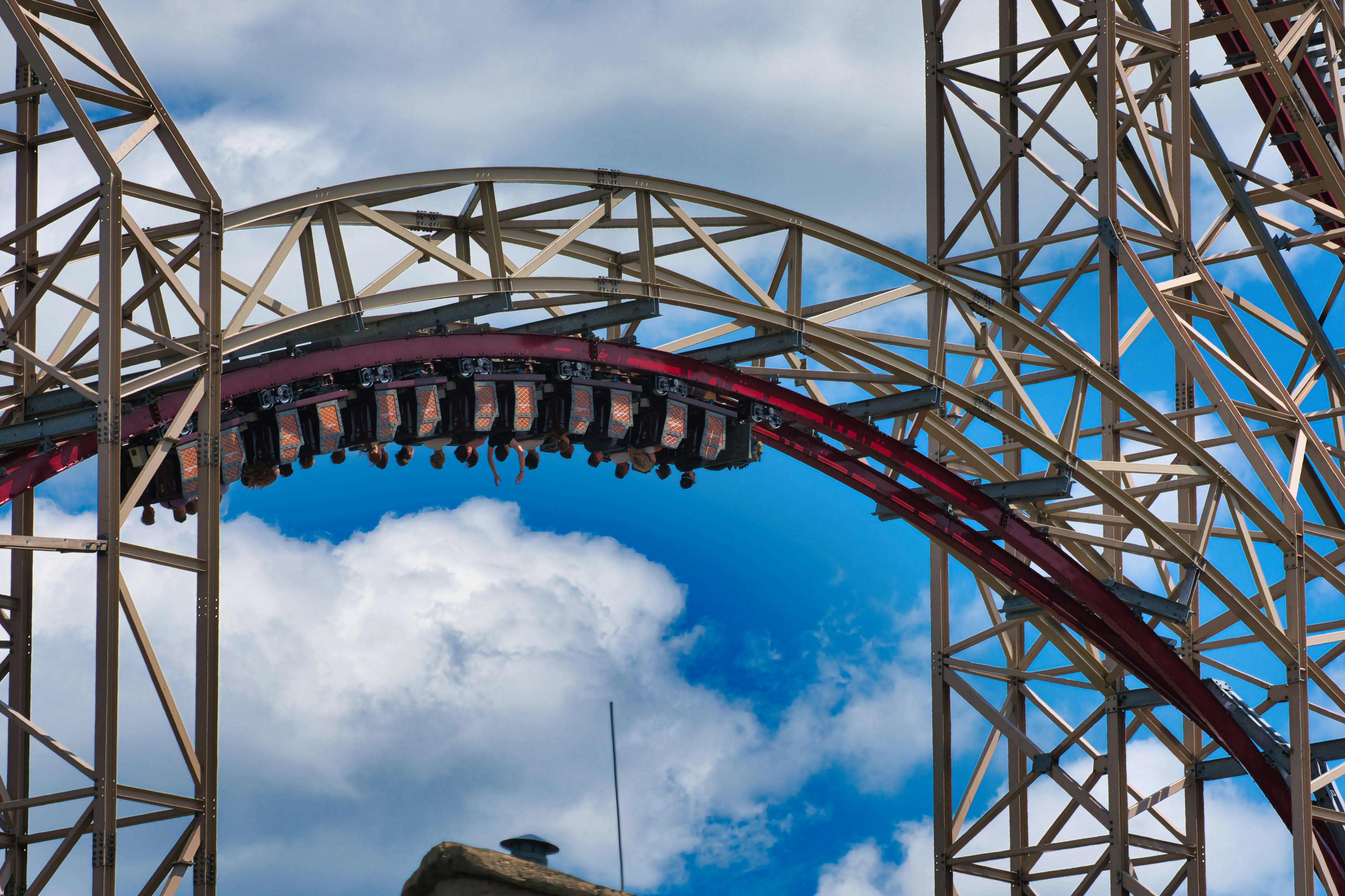 Zadra — hybrid horror in hyperdrive. From the moment you crest the 62.8 m lift, Zadra drops you into a flawless 90° plunge before tearing through a Zero‑G stall, double Zero‑G roll, and razor-sharp transitions—all at 121 km/h. With relentless pacing and over 1.3 km of I‑Box track, it's Europe’s apex RMC beast. Type: Hybrid Coaster (RMC I‑Box Track) Opened: 22 August 2019 Height: 62.8 m | Drop: 90° Length: 1,316 m Top Speed: 121 km/h Inversions: 3 (Zero‑G Stall, 2 Zero‑G Rolls) Duration: ~1:50 min G‑Force: ~4 g Trains: 2 trains with 6 cars (2 × 2 riders) Capacity: ~1,050 riders/hou | A roller coaster climbs through the sky.