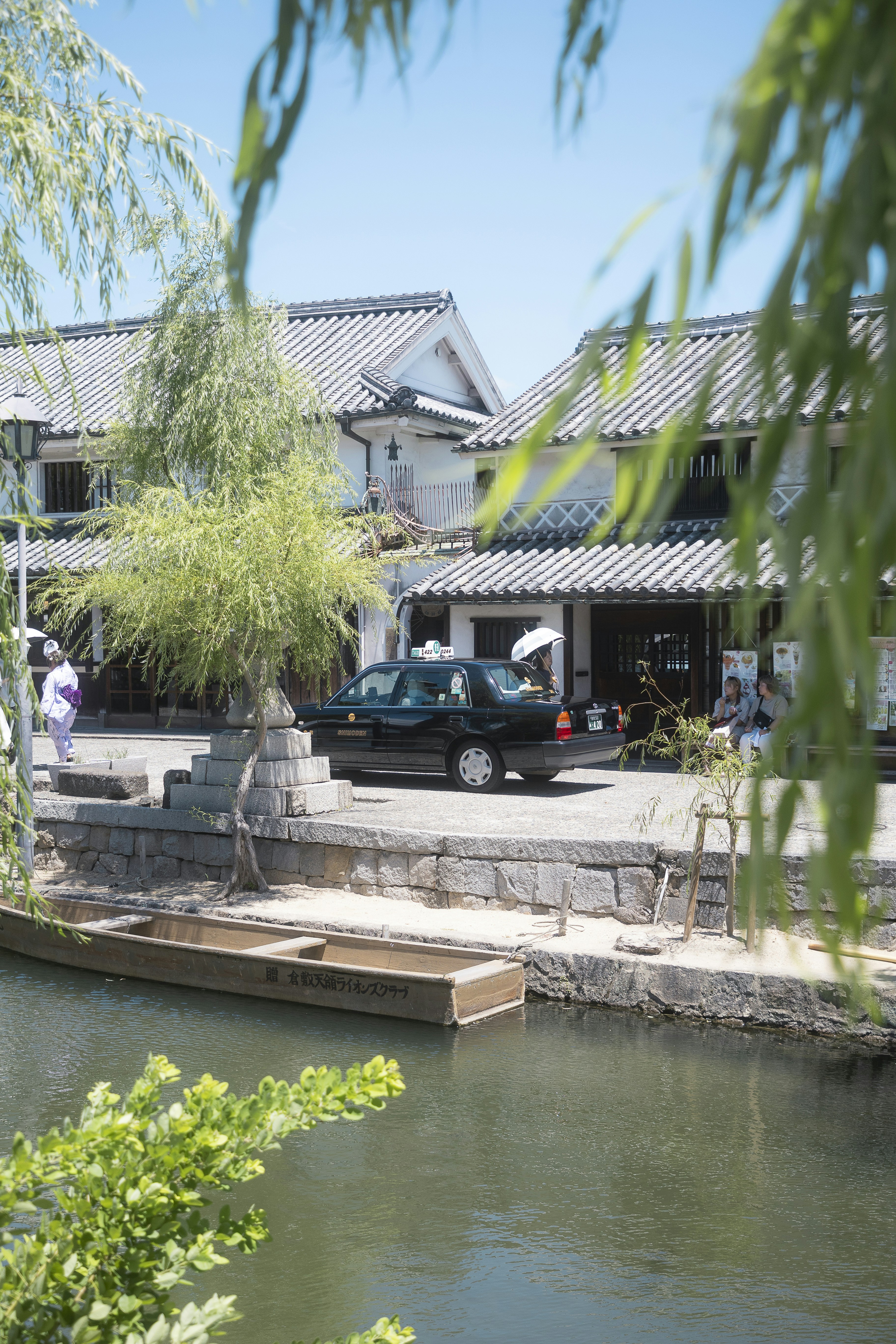 A black car parks by a canal in japan.