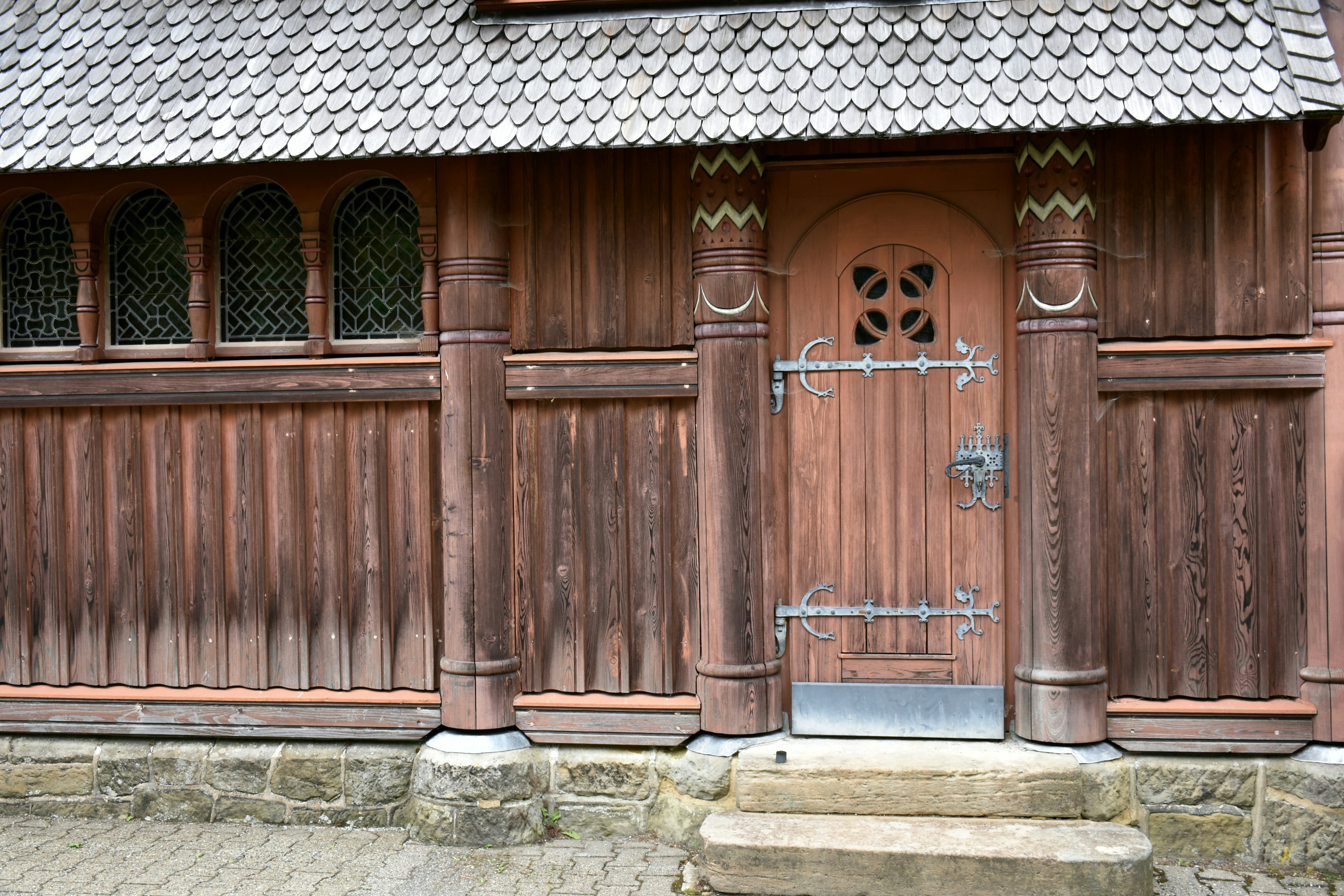 The side of a wooden church (Travel - church - Europe) | A rustic wooden building with door and windows.