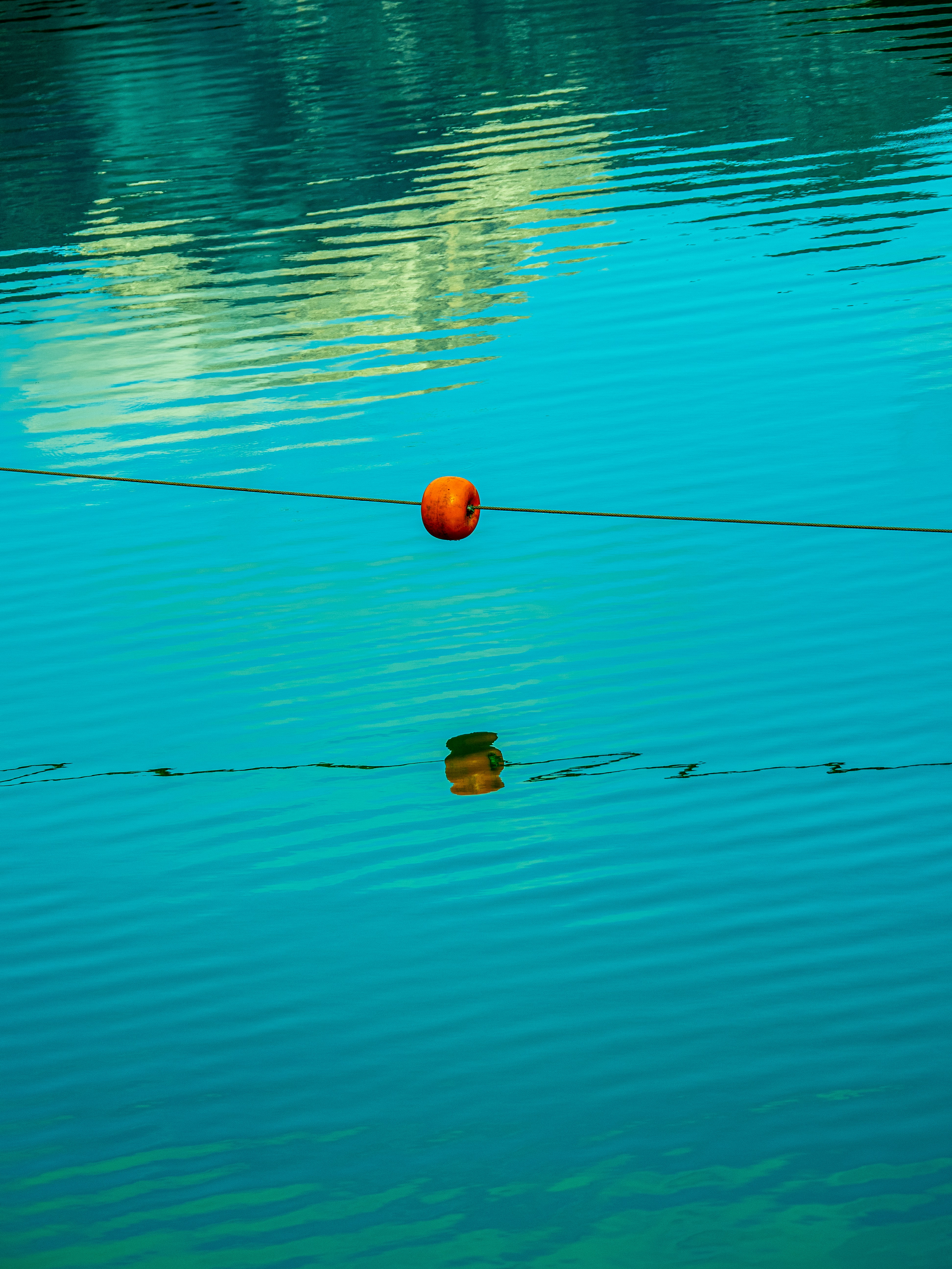 Orange buoy floats on shimmering turquoise water.