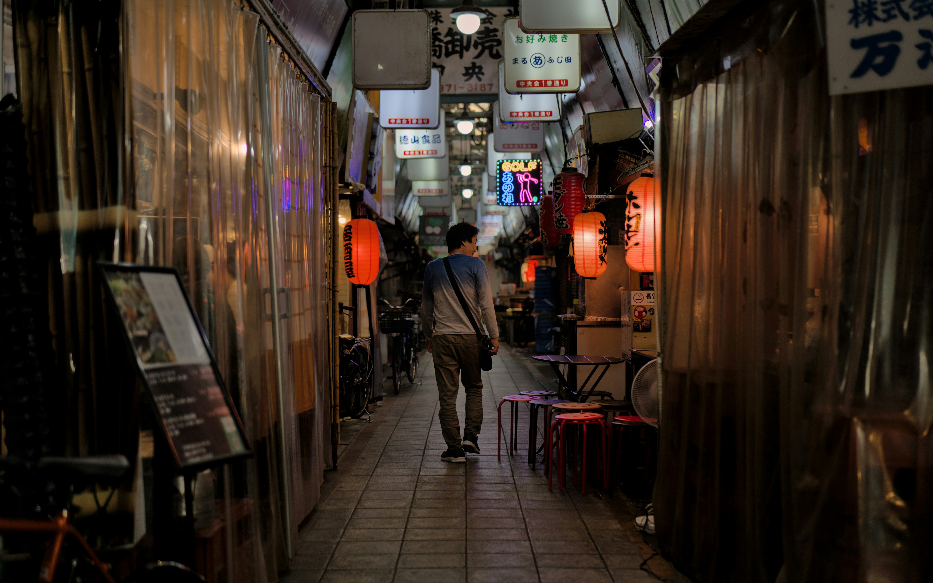 A man walks through an alley lined with bars and eateries in Osaka's Tsuhurashi, also known as Korea Town. 2025-06-28 | Man walks through a vibrant and bustling alley.