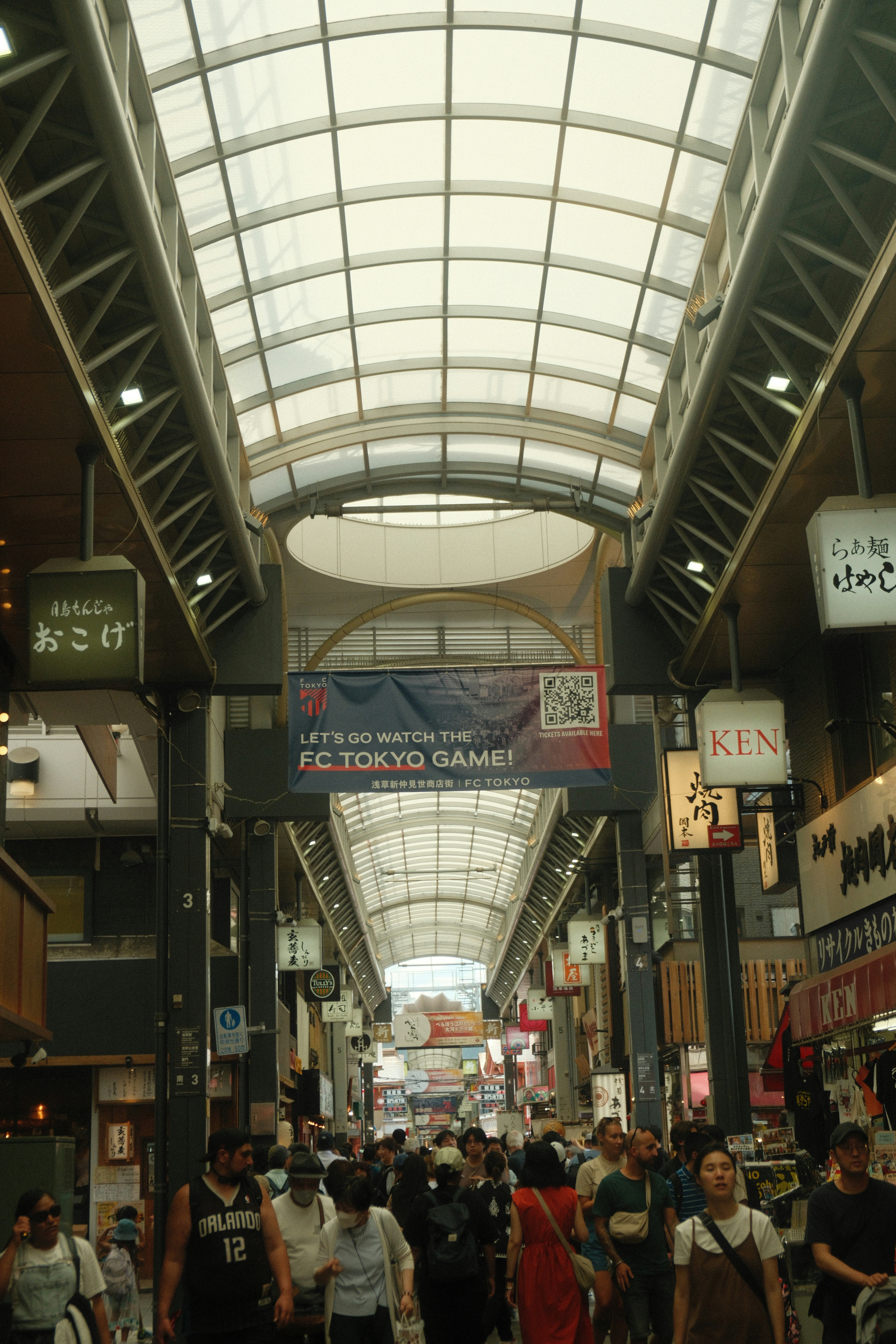 Crowded shopping street with a glass roof.