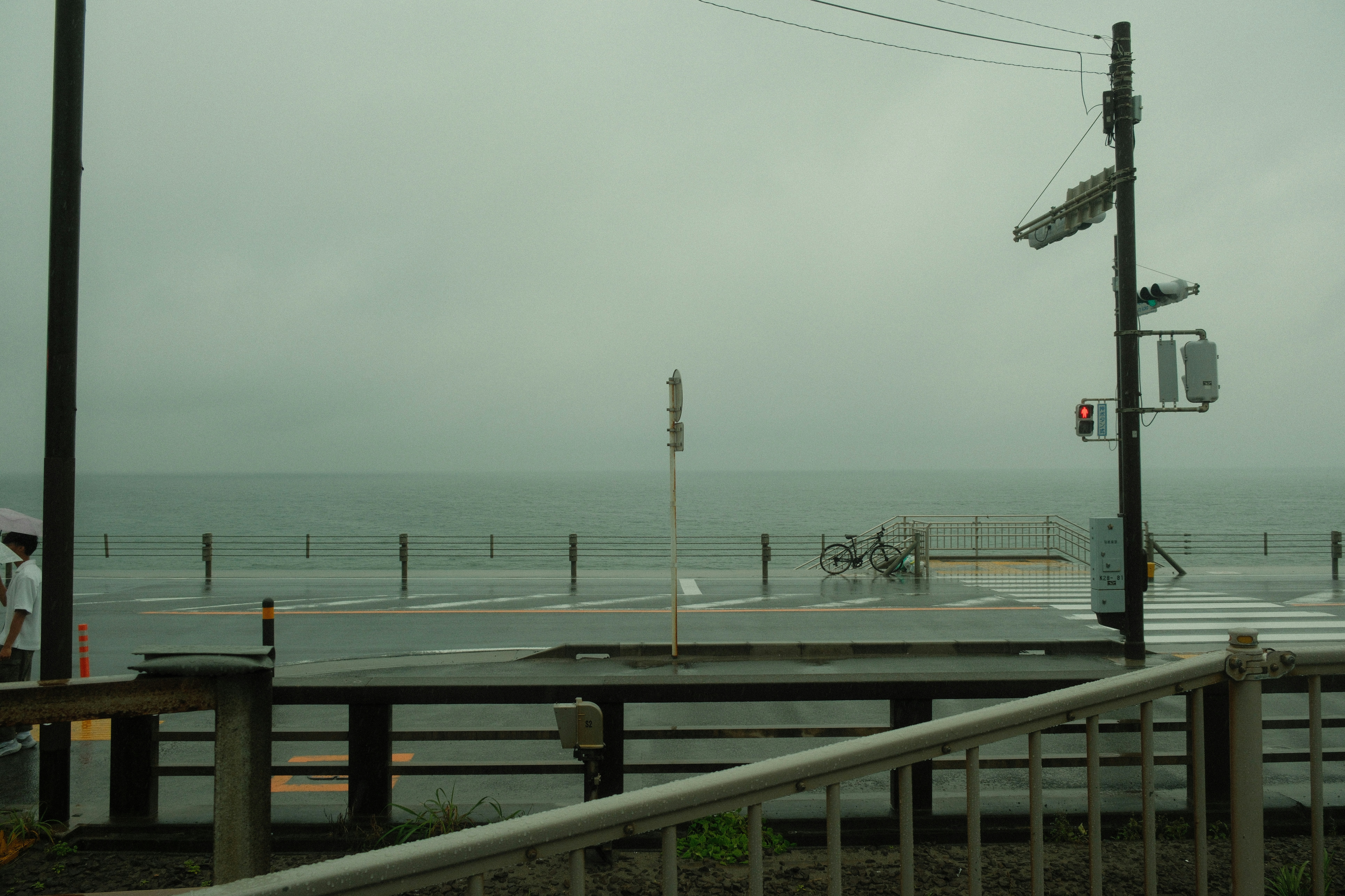 Rainy day scene with ocean and crosswalk.