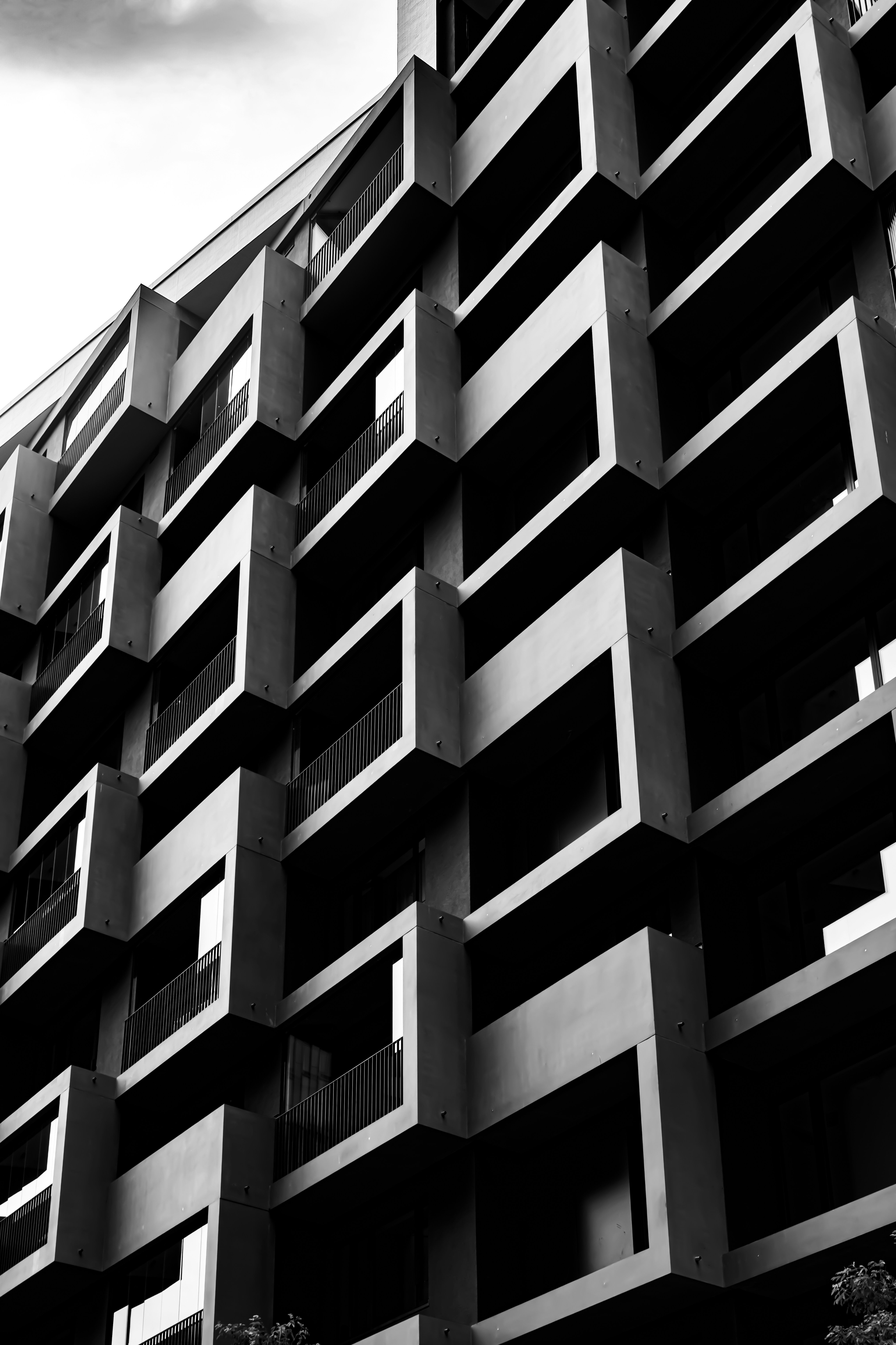 Monochromatic facade of a modern building showcasing bold geometric shapes and structured balconies.