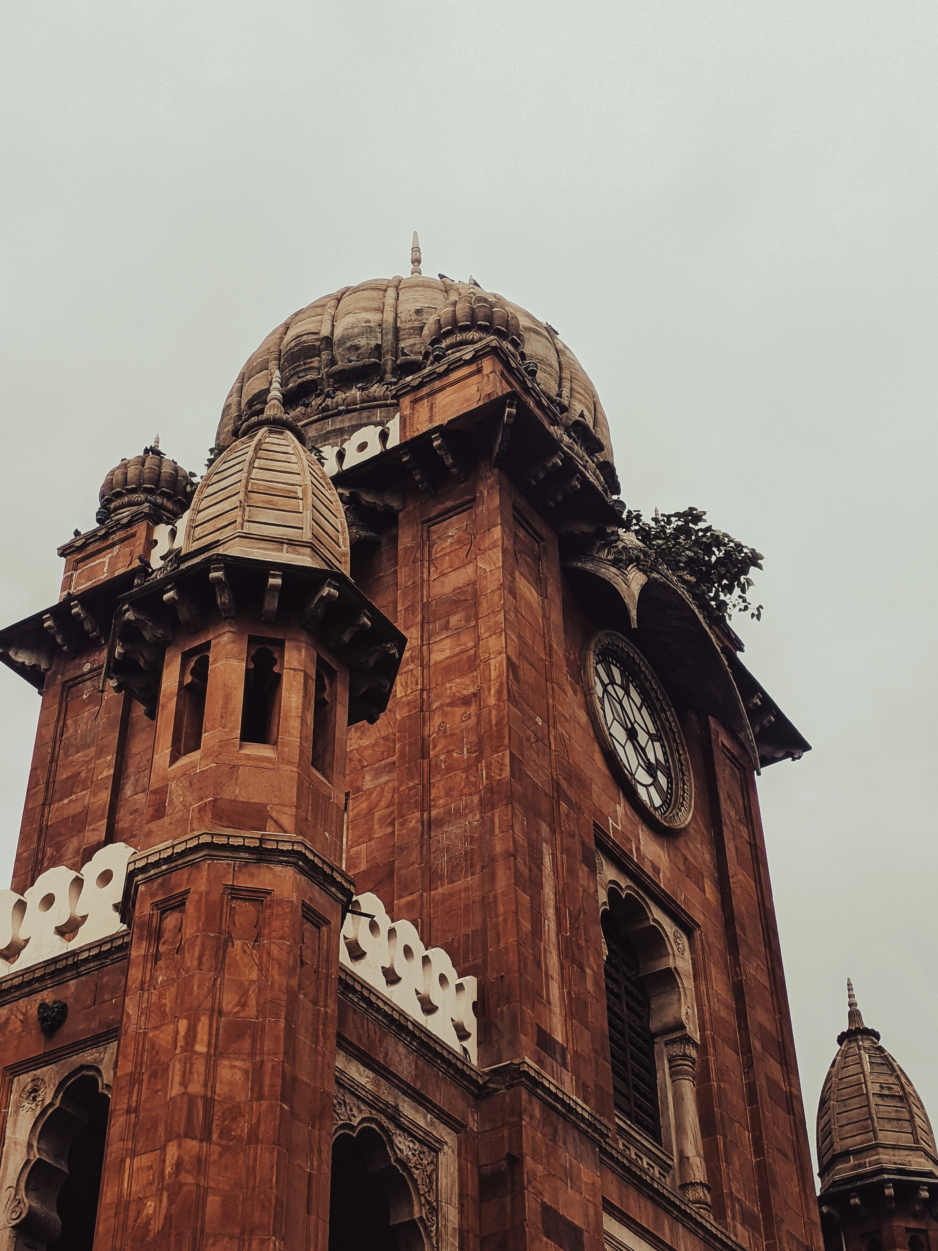Gandhi Hall in Indore; a historic landmark known for its Indo-Gothic architecture and cultural significance. | An old, grand building with a clock on it.