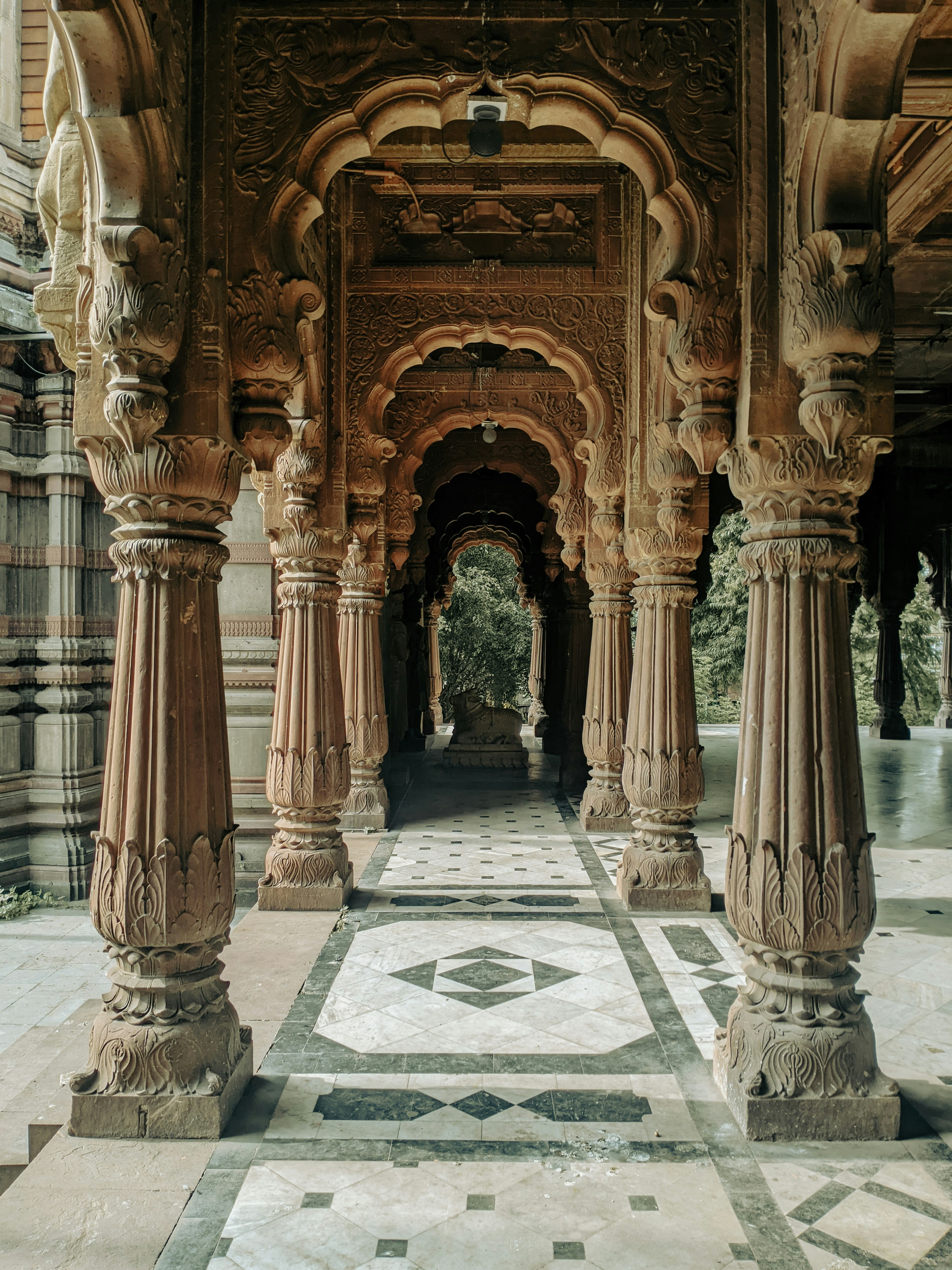 A majestic hallway lined with ornate pillars, showcasing traditional architectural elegance and timeless craftsmanship. | Here is a short caption for the image: ornate archways line a stone pathway.
