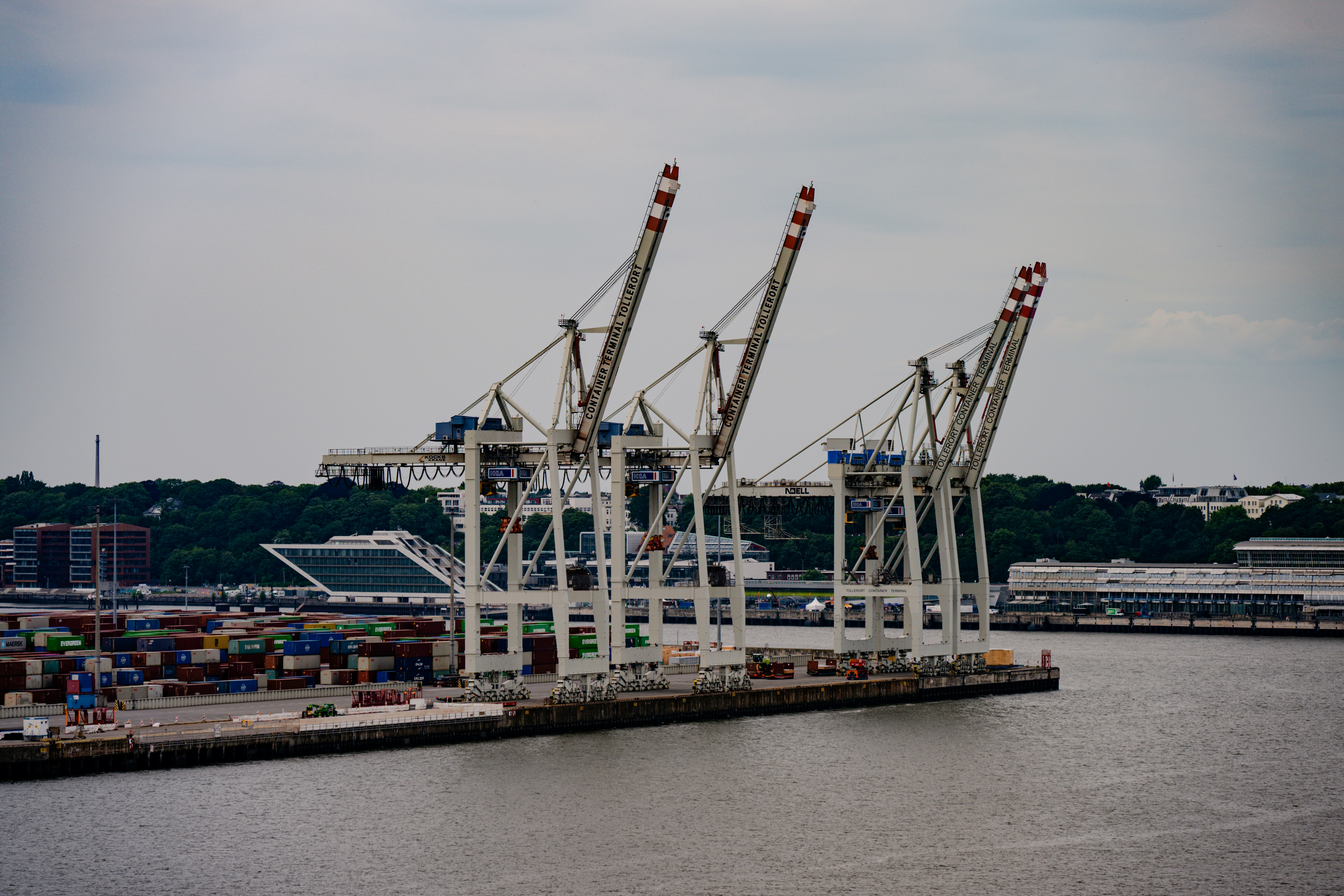 Harbor cranes stand tall in front of a cloudy sky.