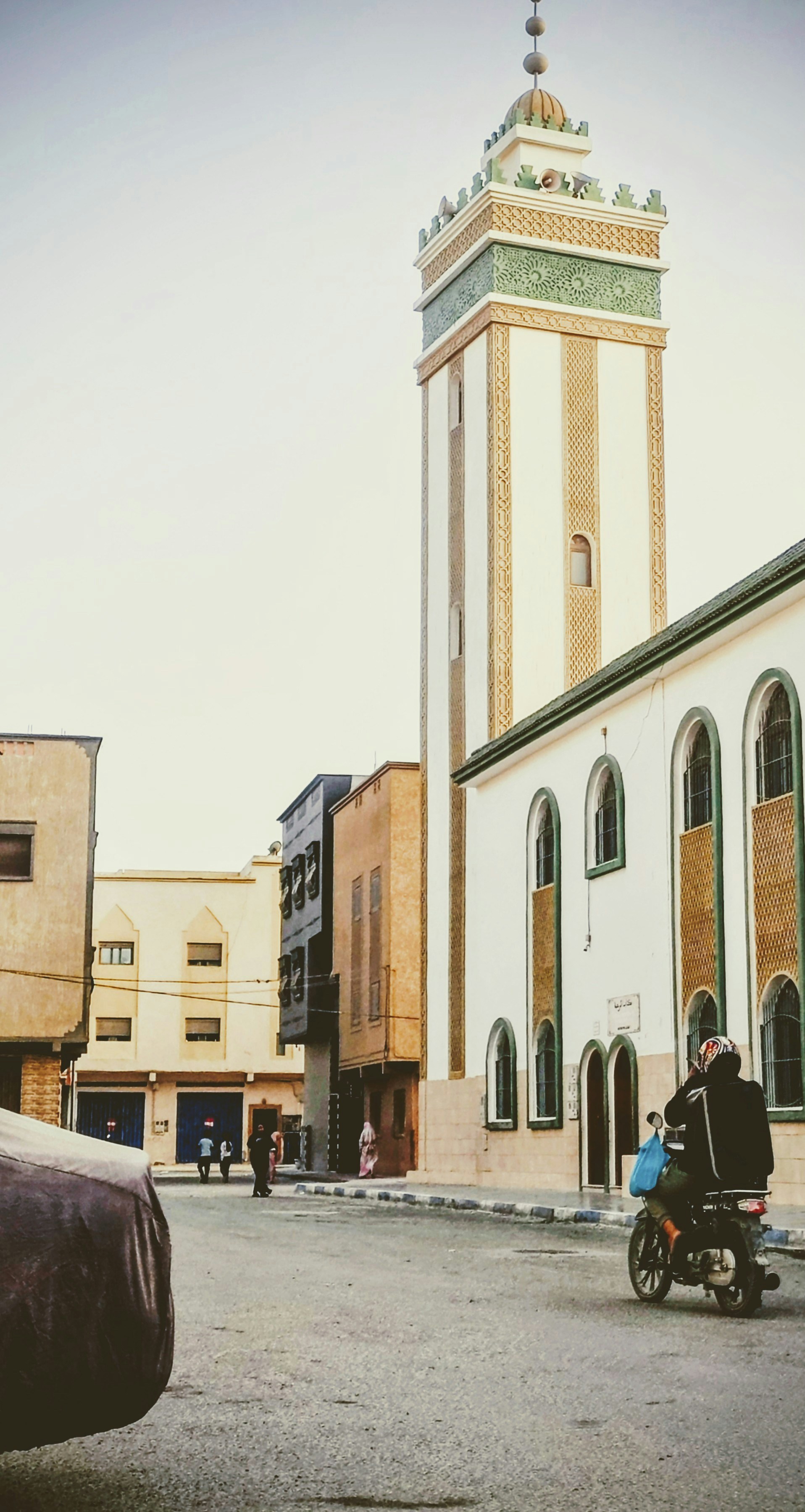 A mosque minaret stands tall in a city street.