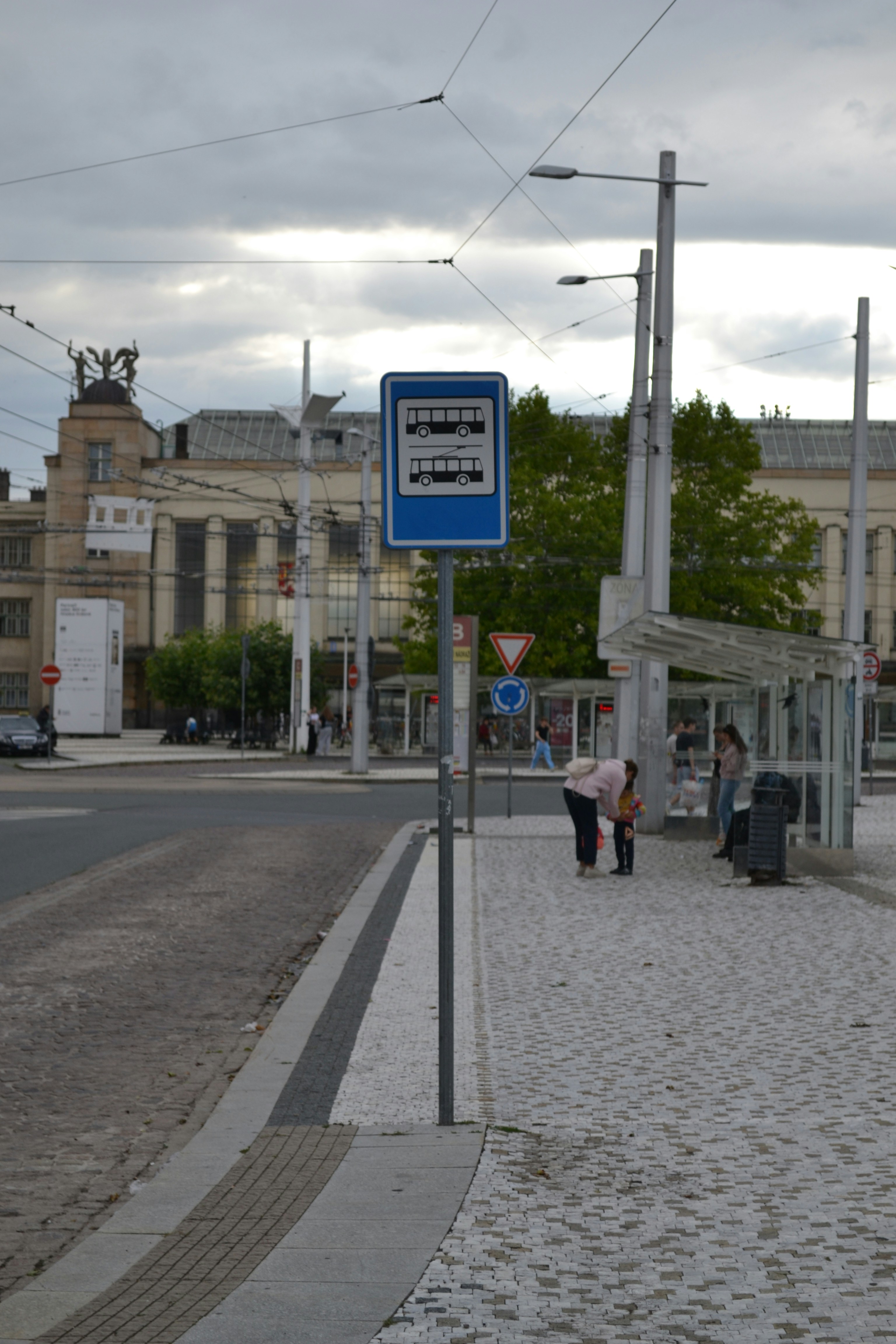 A bus stop sign stands on a city sidewalk.