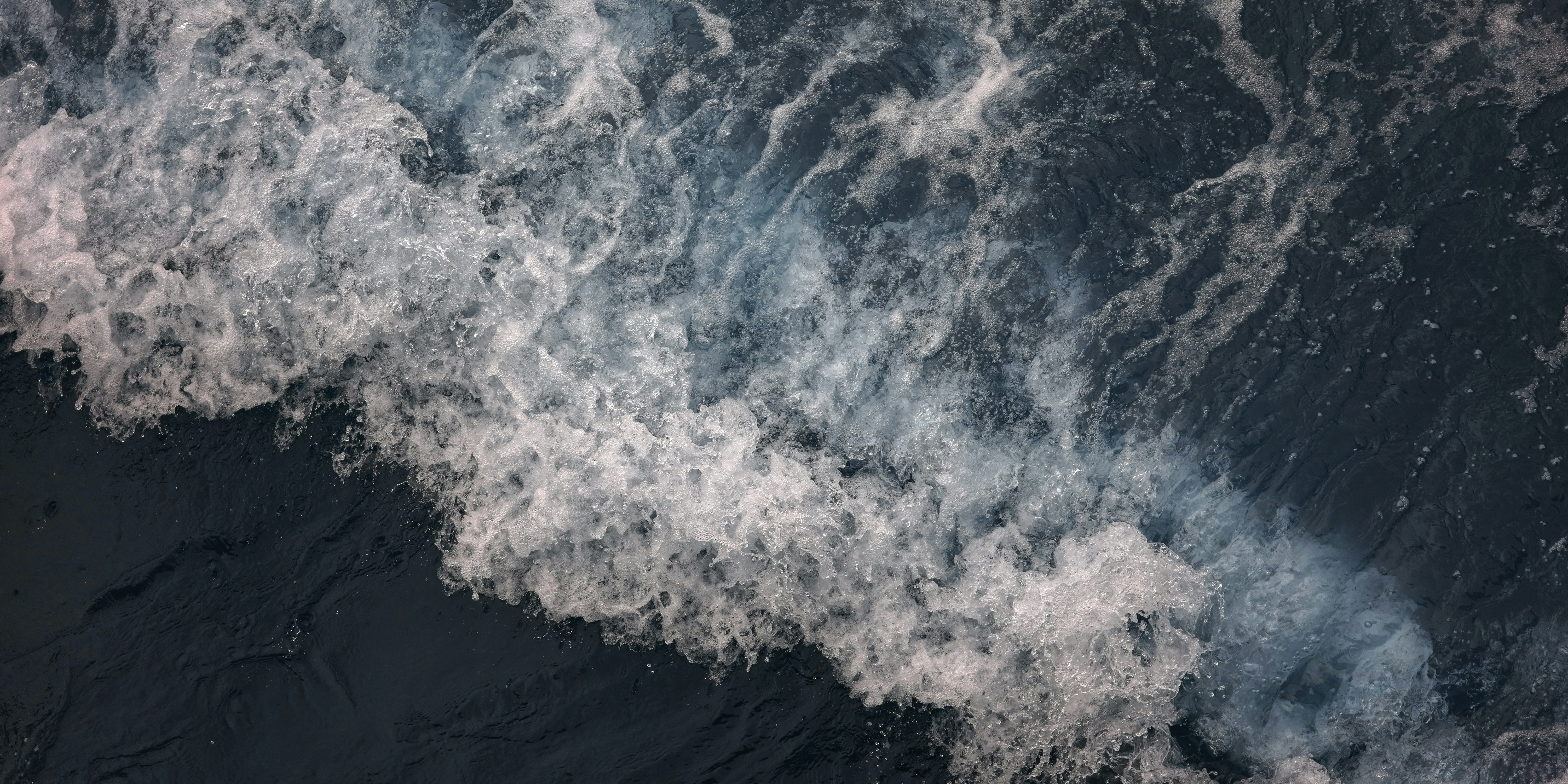 Foamy waves crashing against a dark sea surface, illustrating the dynamic interplay of water and light.