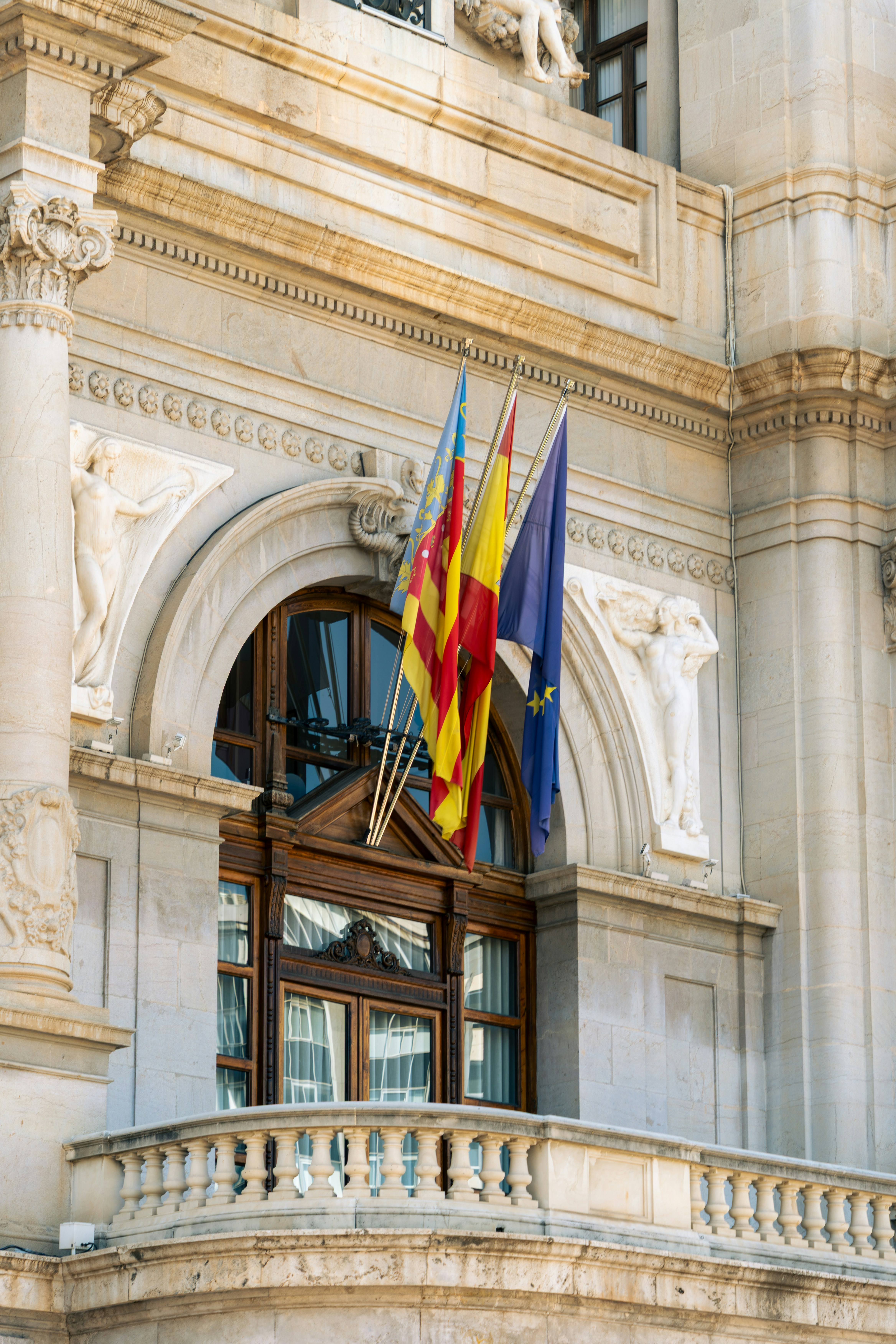 Ajuntament de València (Valencia City Hall) | Flags fly above an ornate building's doorway.