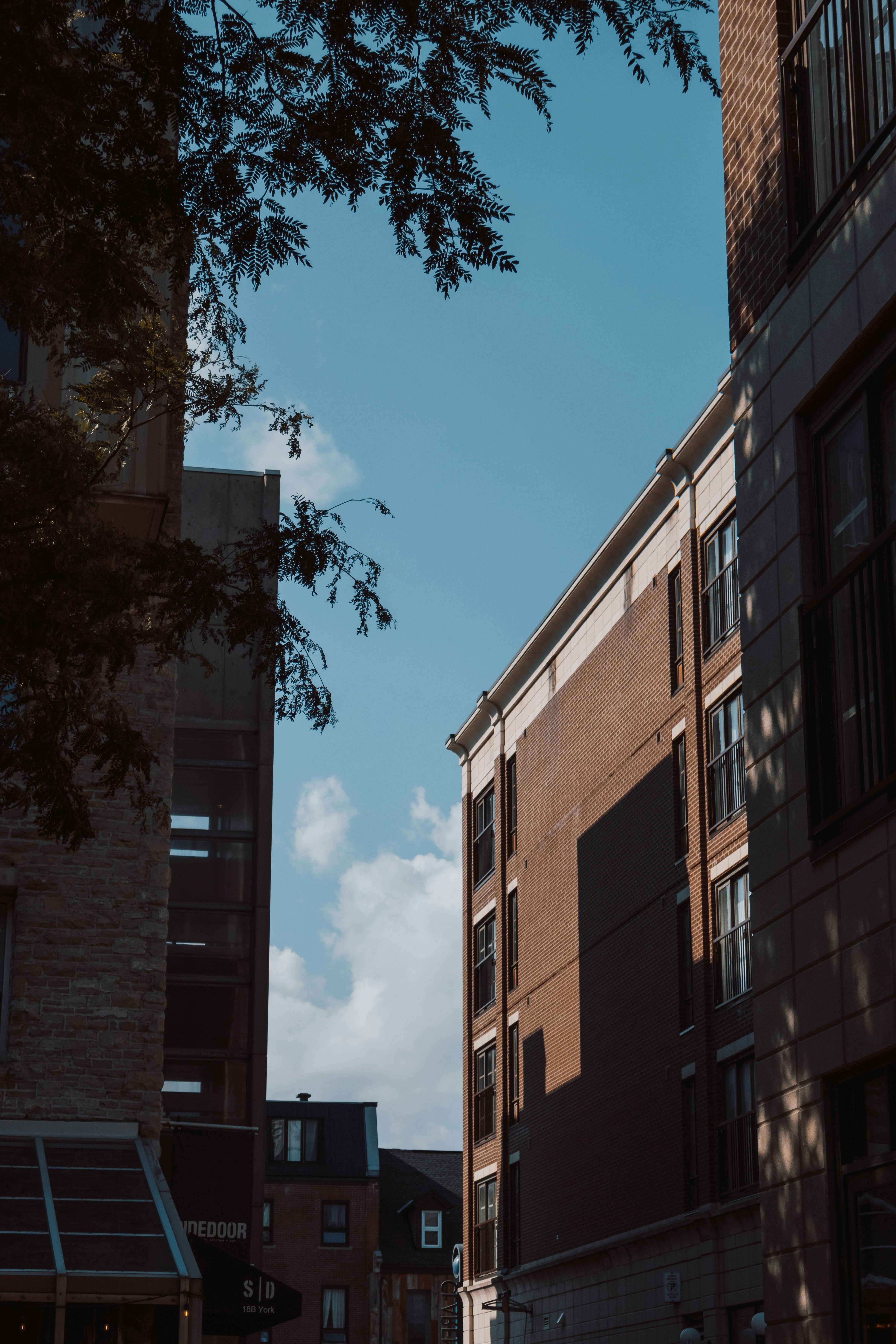 Calm urban alley framed by buildings and a soft summer sky. | Buildings are framing a blue sky.