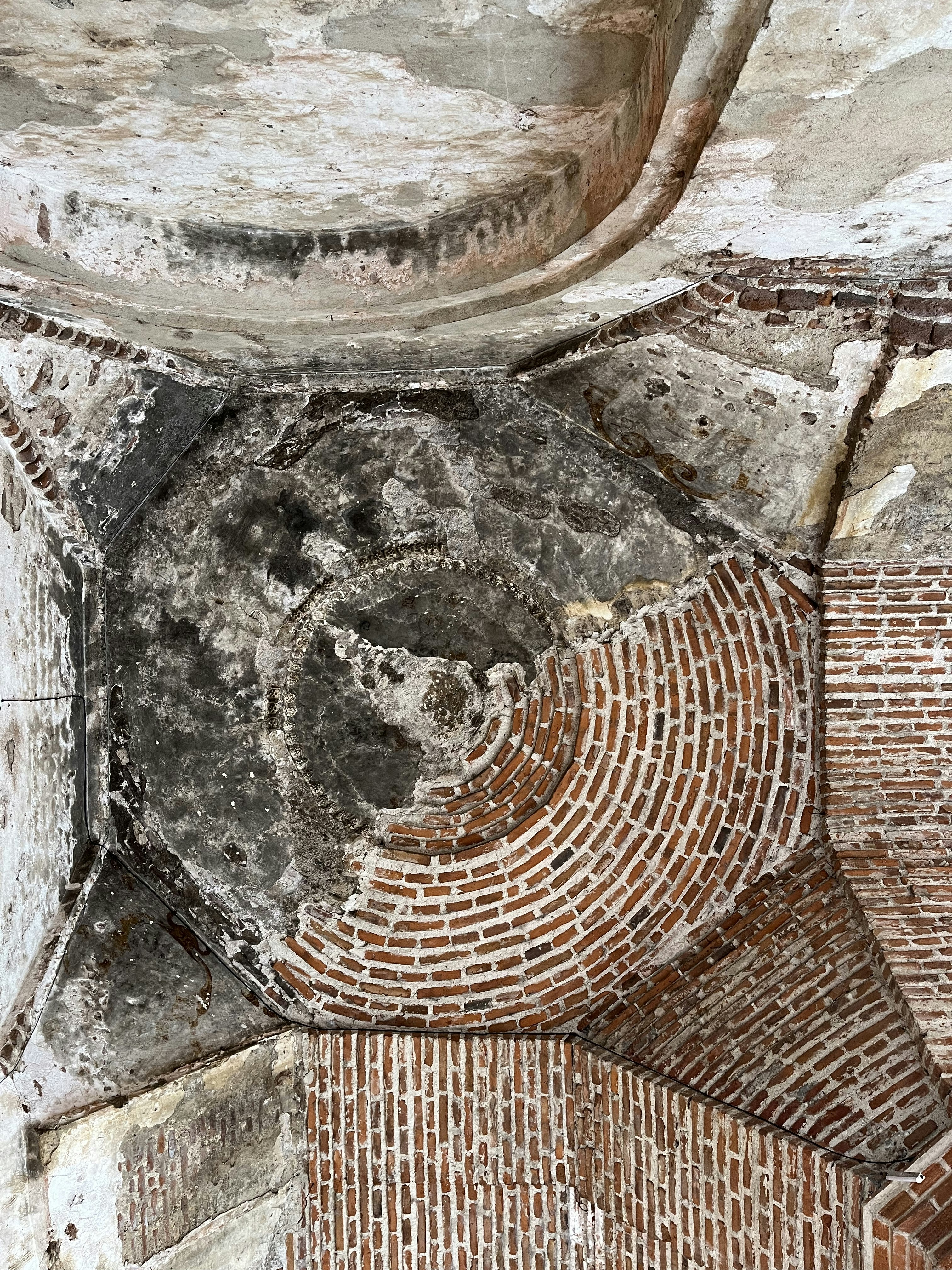 Intricate brickwork and weathered plaster showcase the remnants of a historic structure, highlighting the passage of time and craftsmanship. The composition invites exploration of its architectural significance.