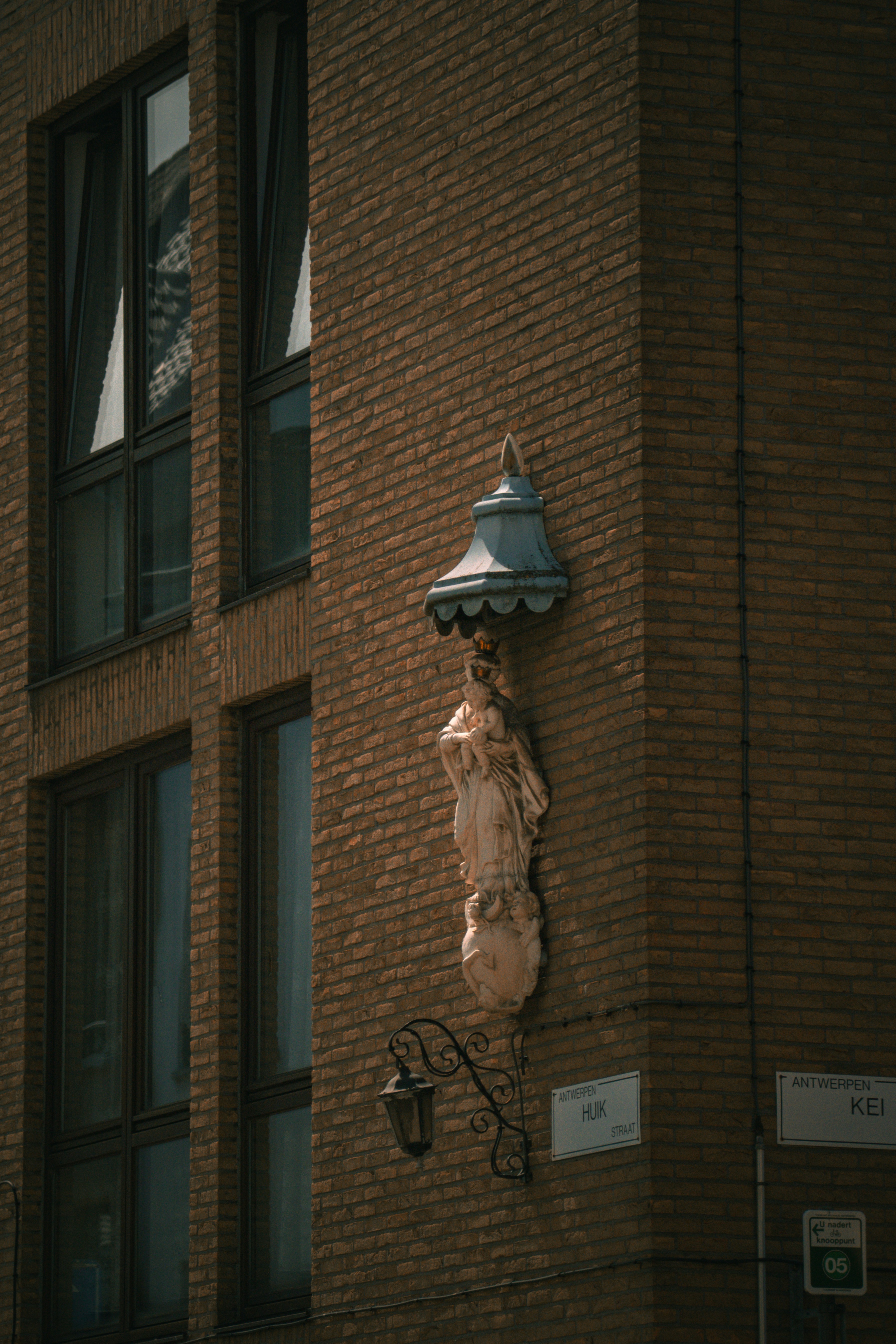 A statue adorns the corner of a brick building.