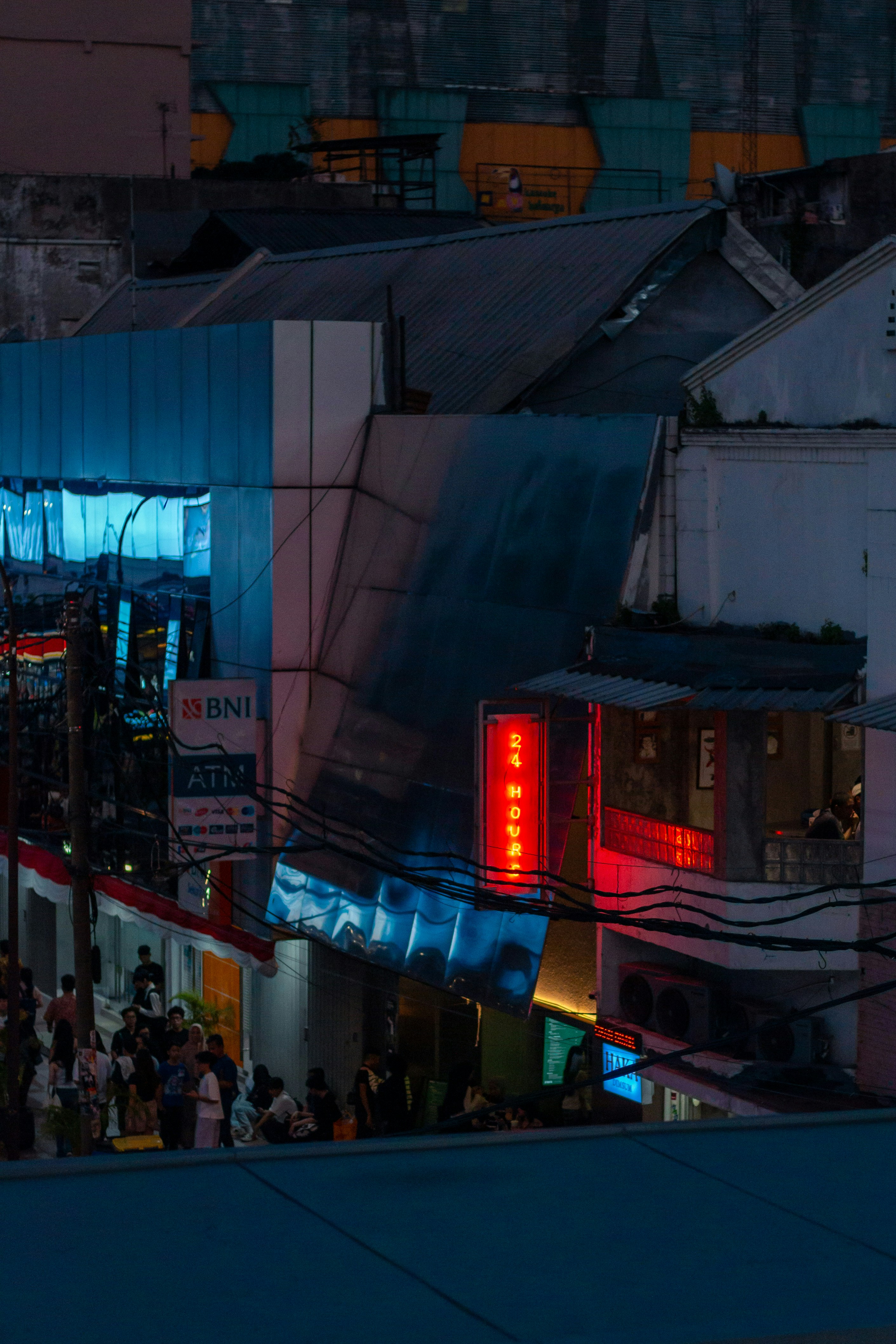 Buildings are illuminated with neon lights at dusk.