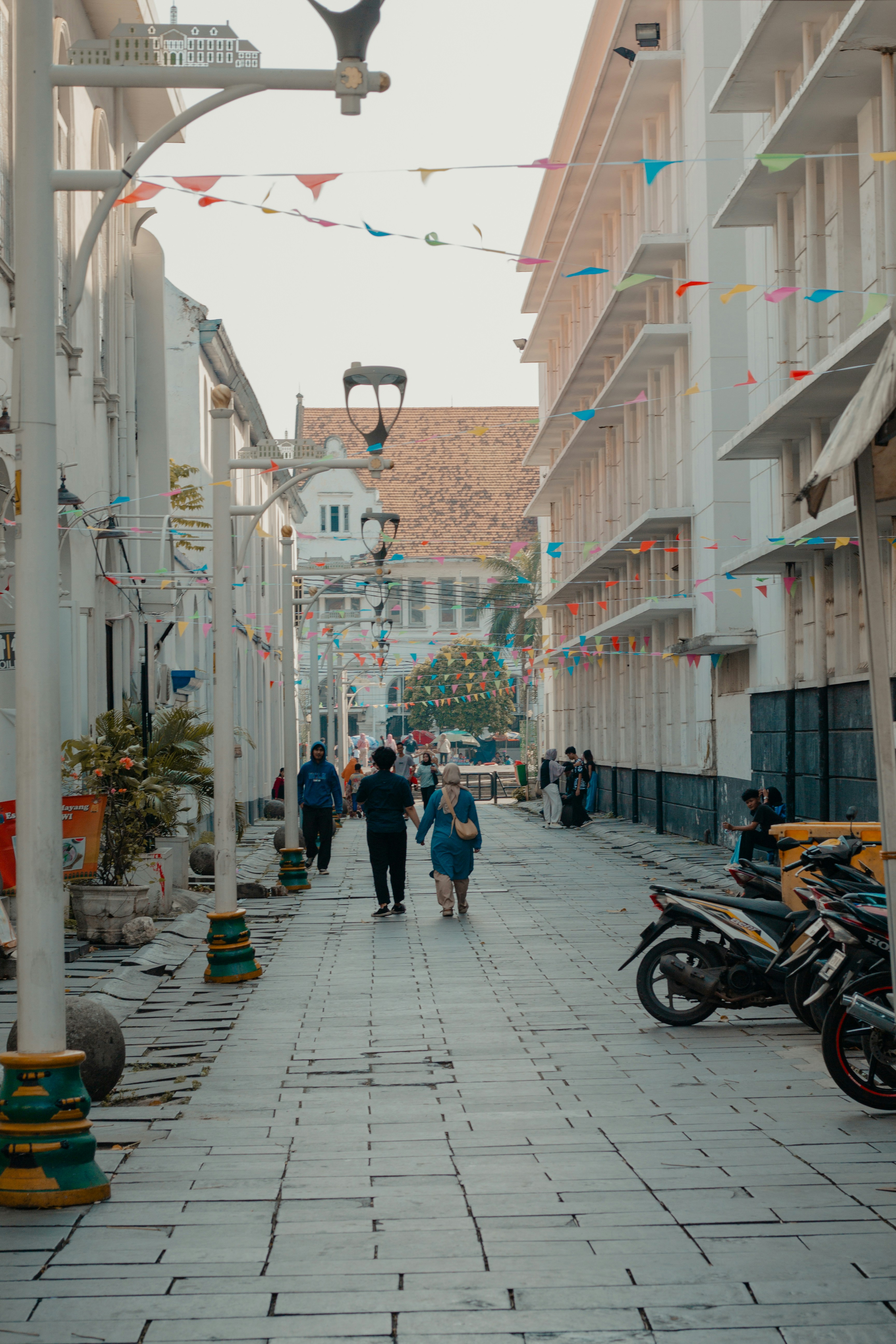 People stroll down a historic street lined with buildings.
