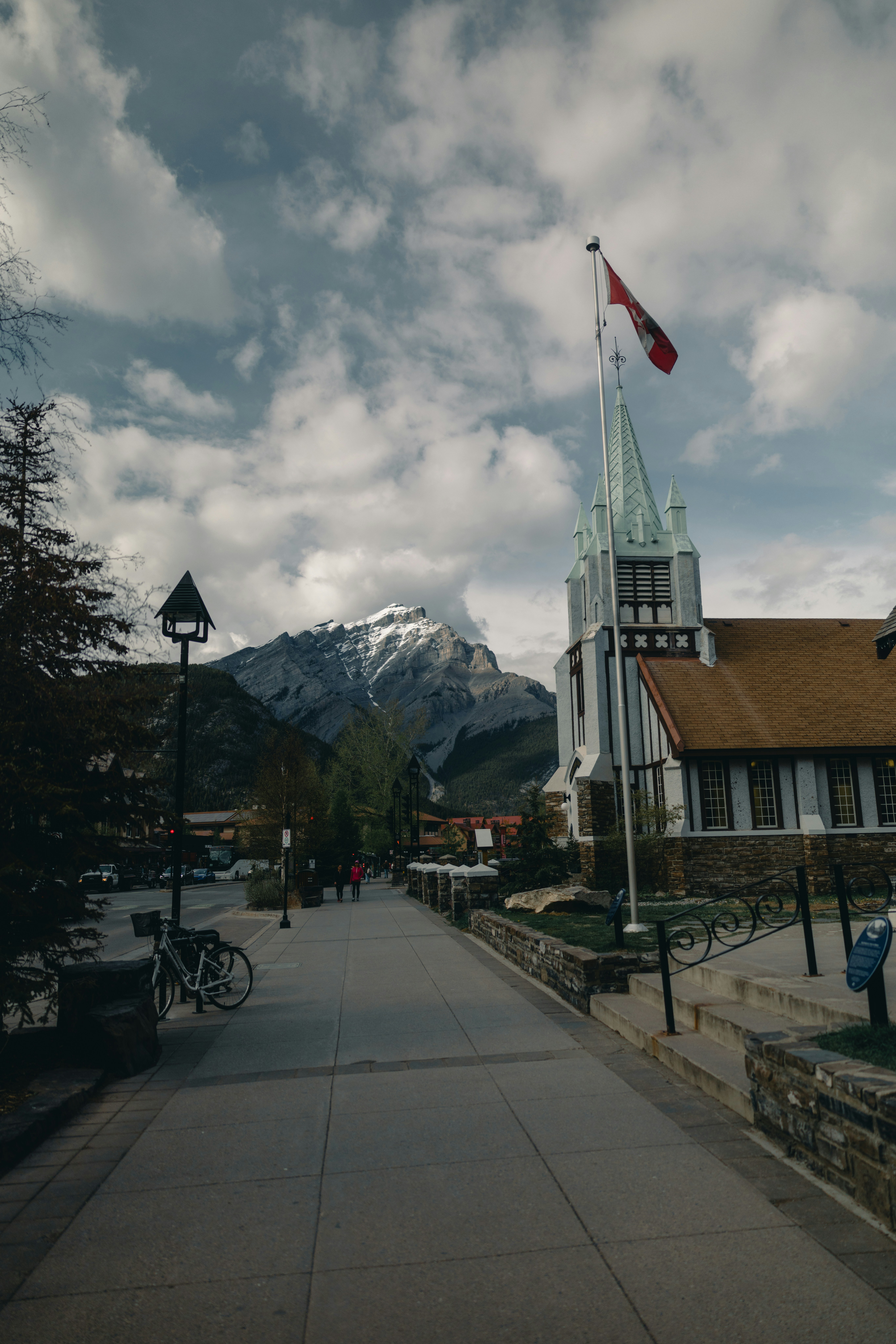 Flag over Alpine Chapel: A Quiet Village Street Toward Snow-Capped Peaks