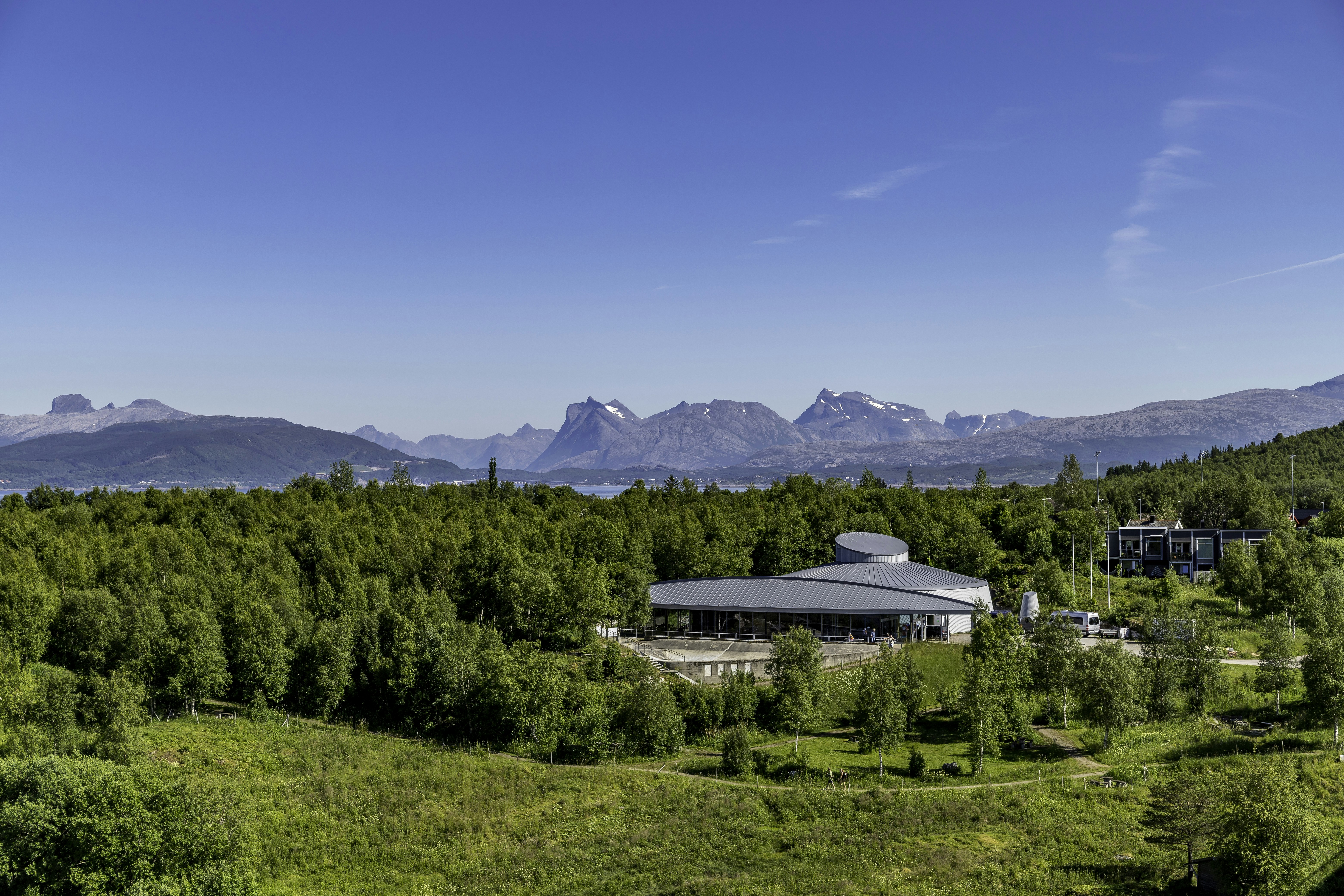 Visitor Center at Saltstraumen Norway | A scenic landscape features buildings, forest, and mountains.