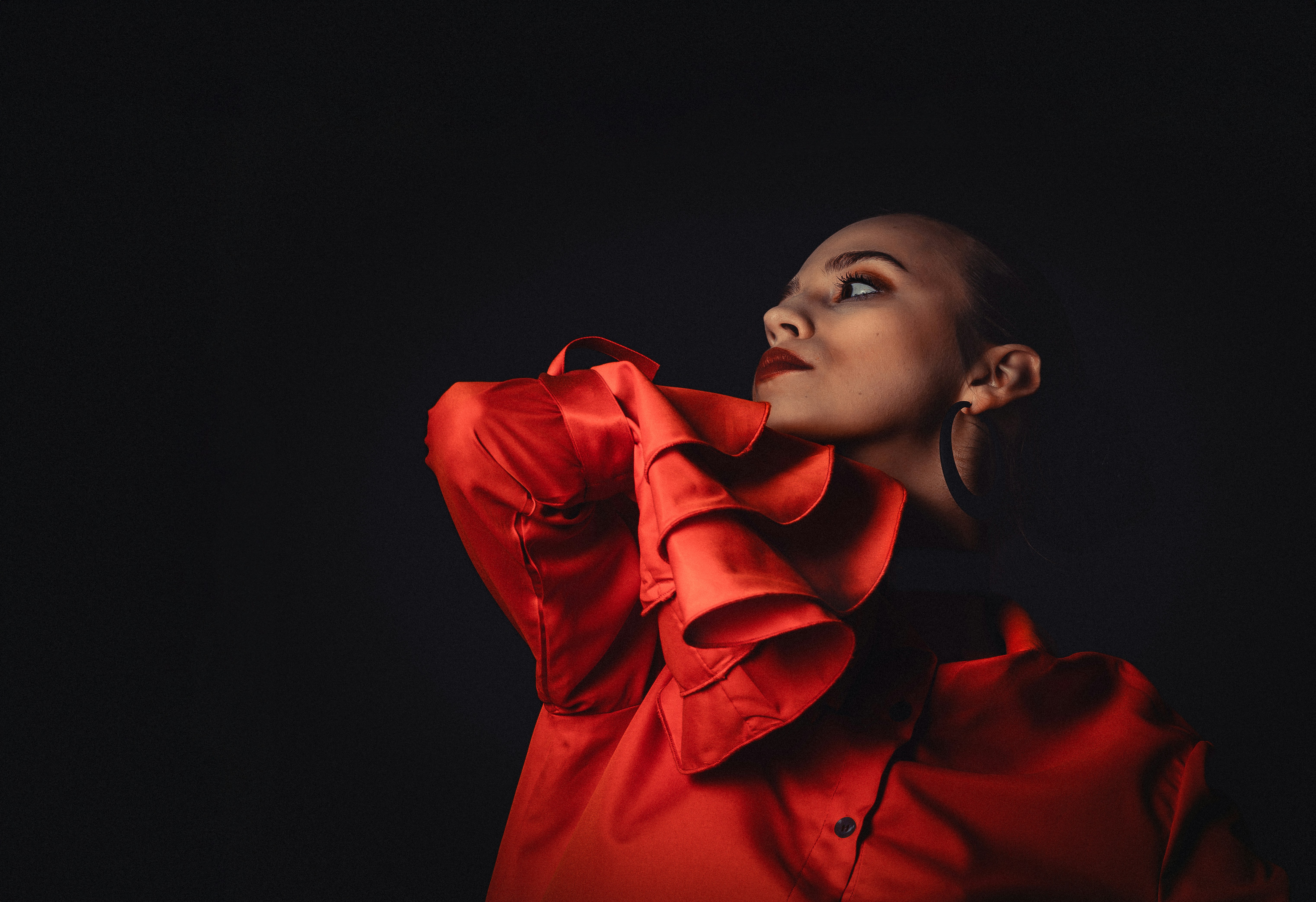 Woman in red is posing against a dark backdrop.