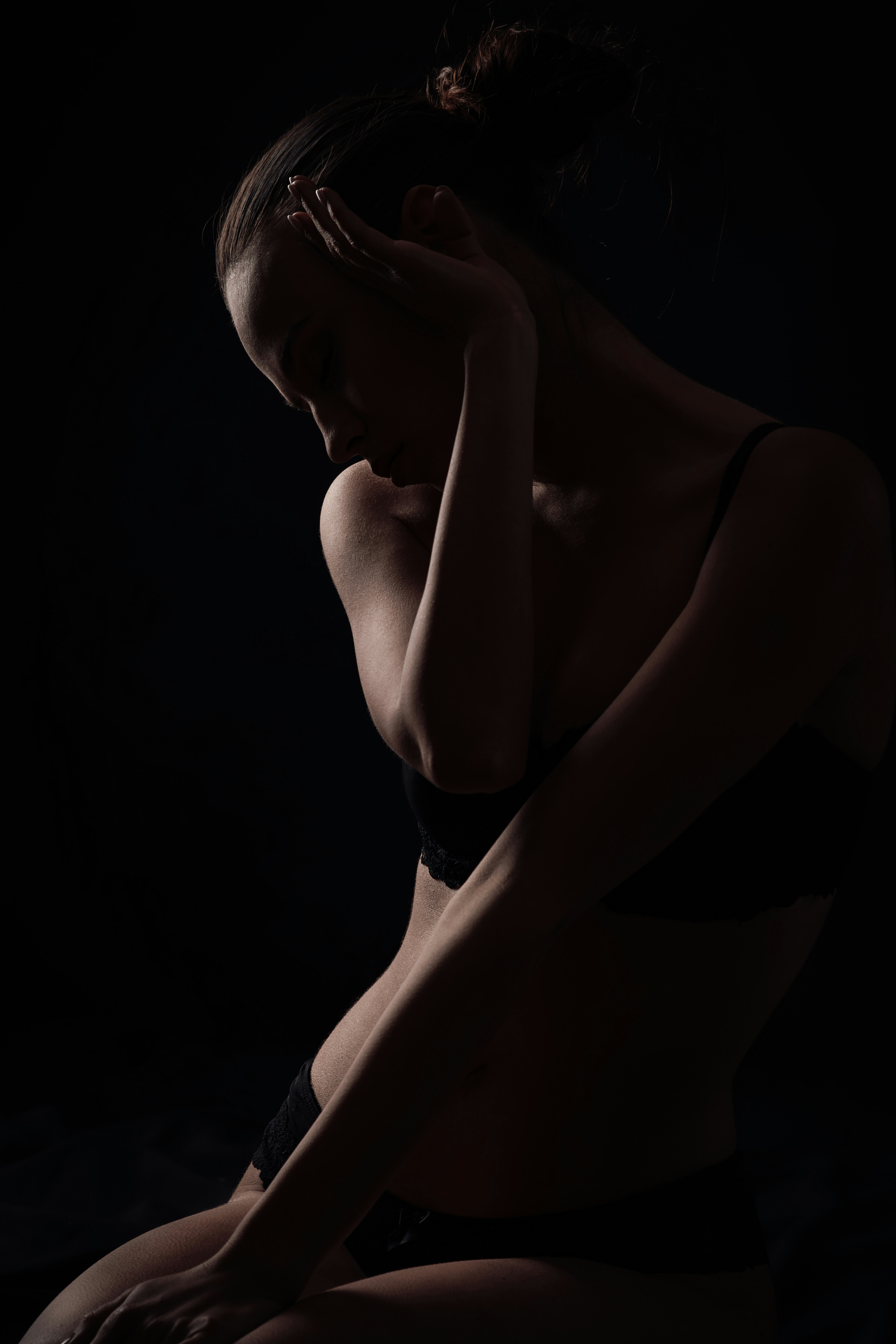 A woman sits thoughtfully in shadow.