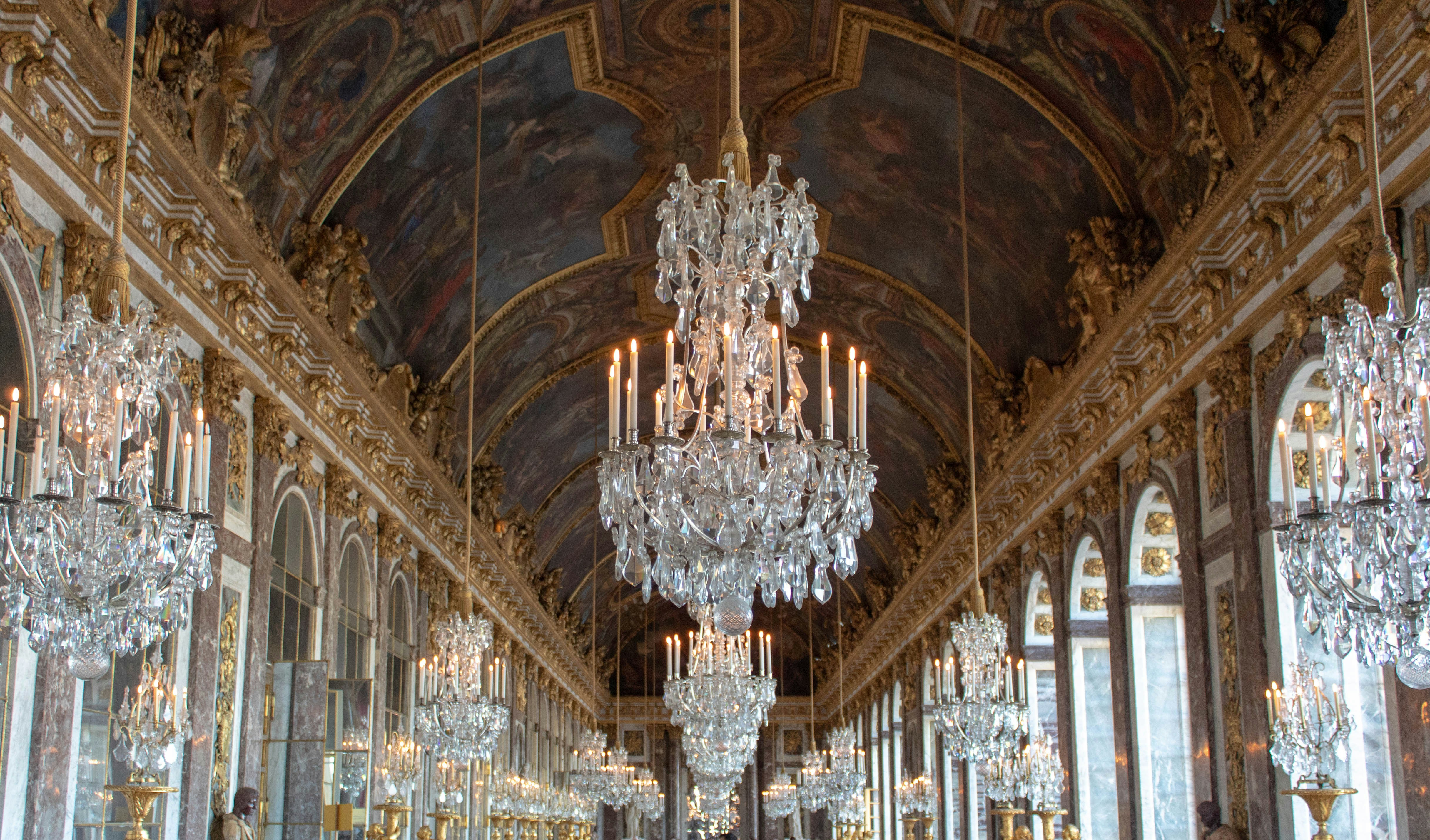 Crystal chandeliers adorn a grand, ornate hall.