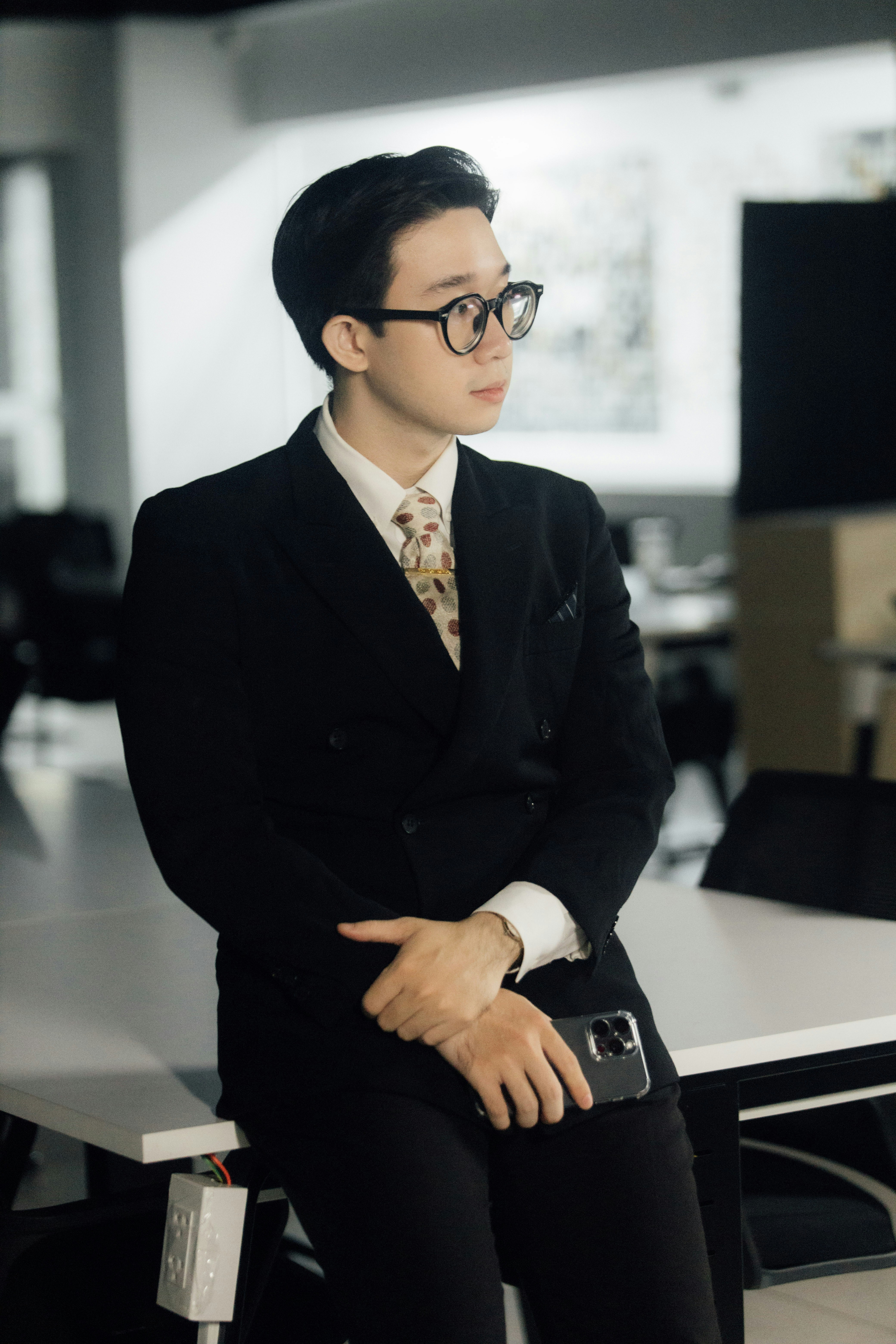 A man in a suit is posing thoughtfully.