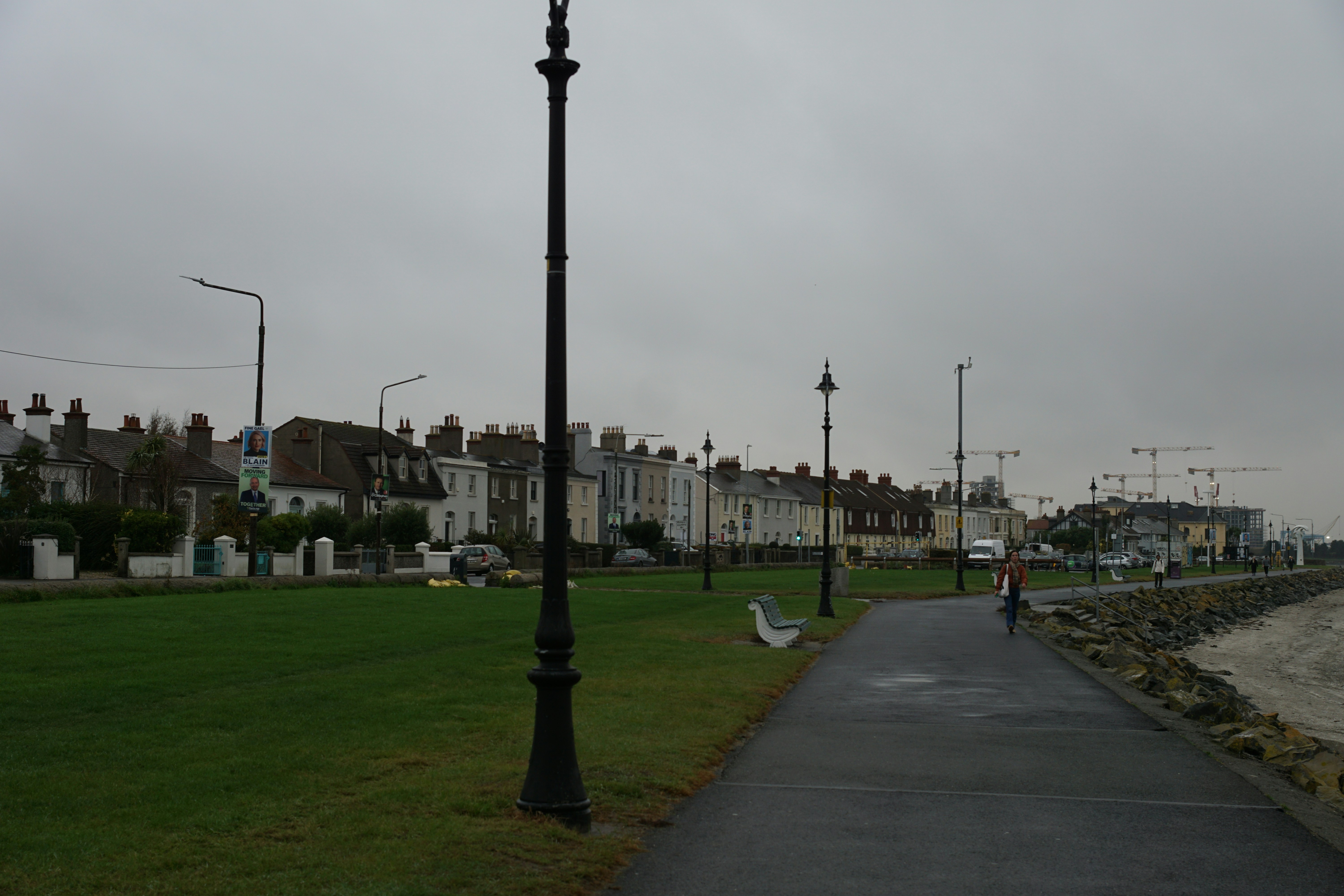 Charming seaside promenade lined with historic buildings and lampposts under a moody sky.