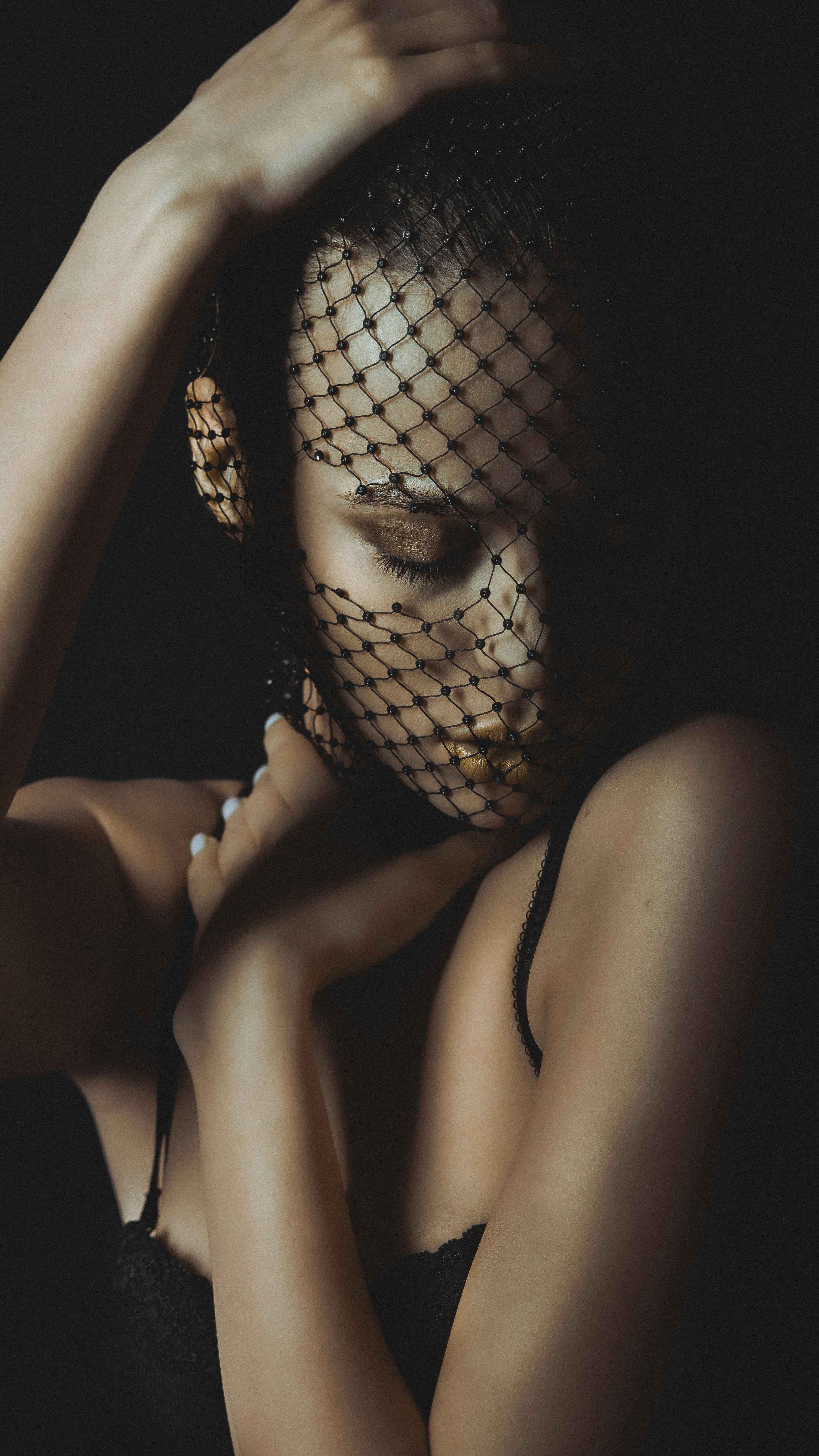 A woman poses with a net over her face.
