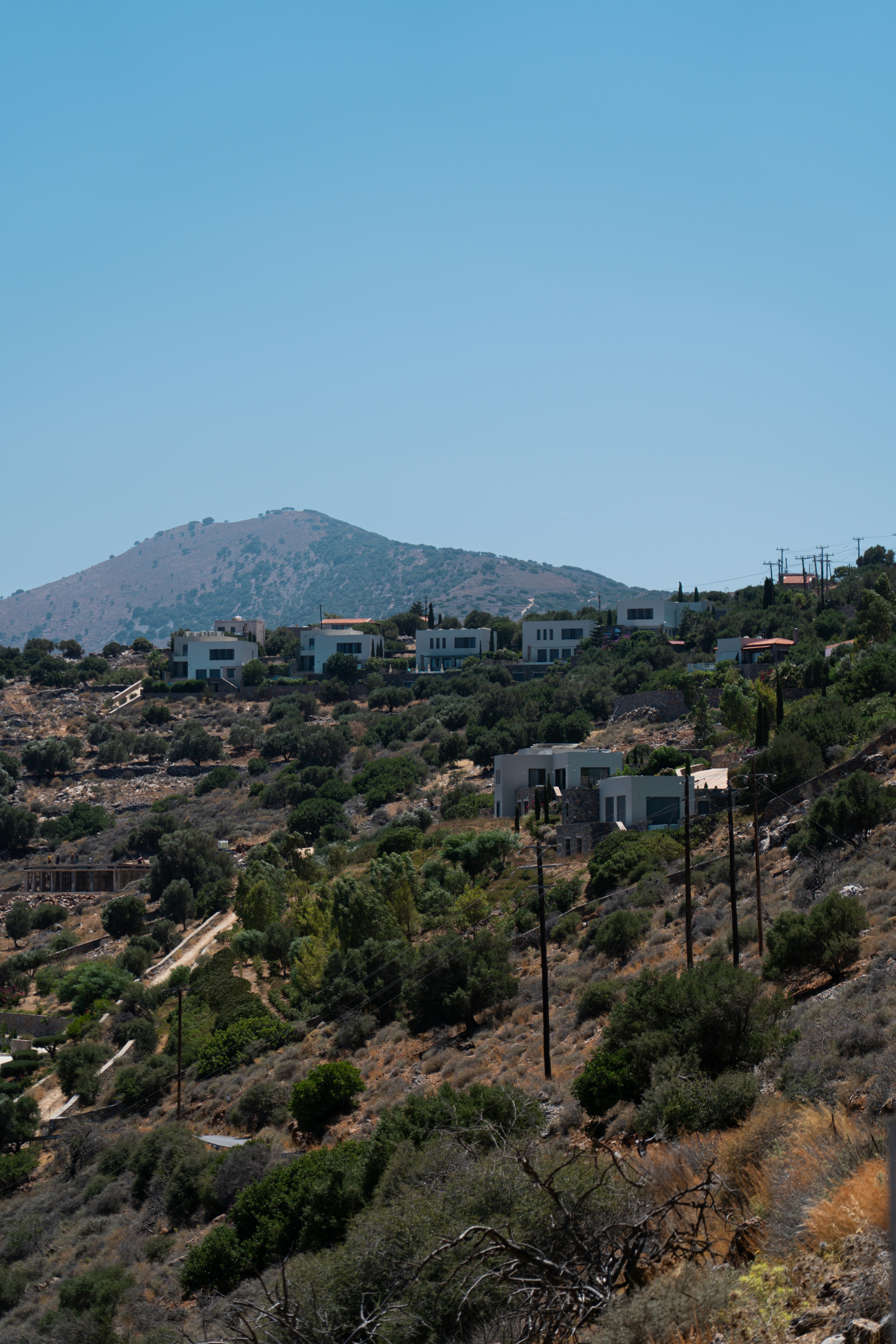Houses dot a hillside beneath a clear blue sky.