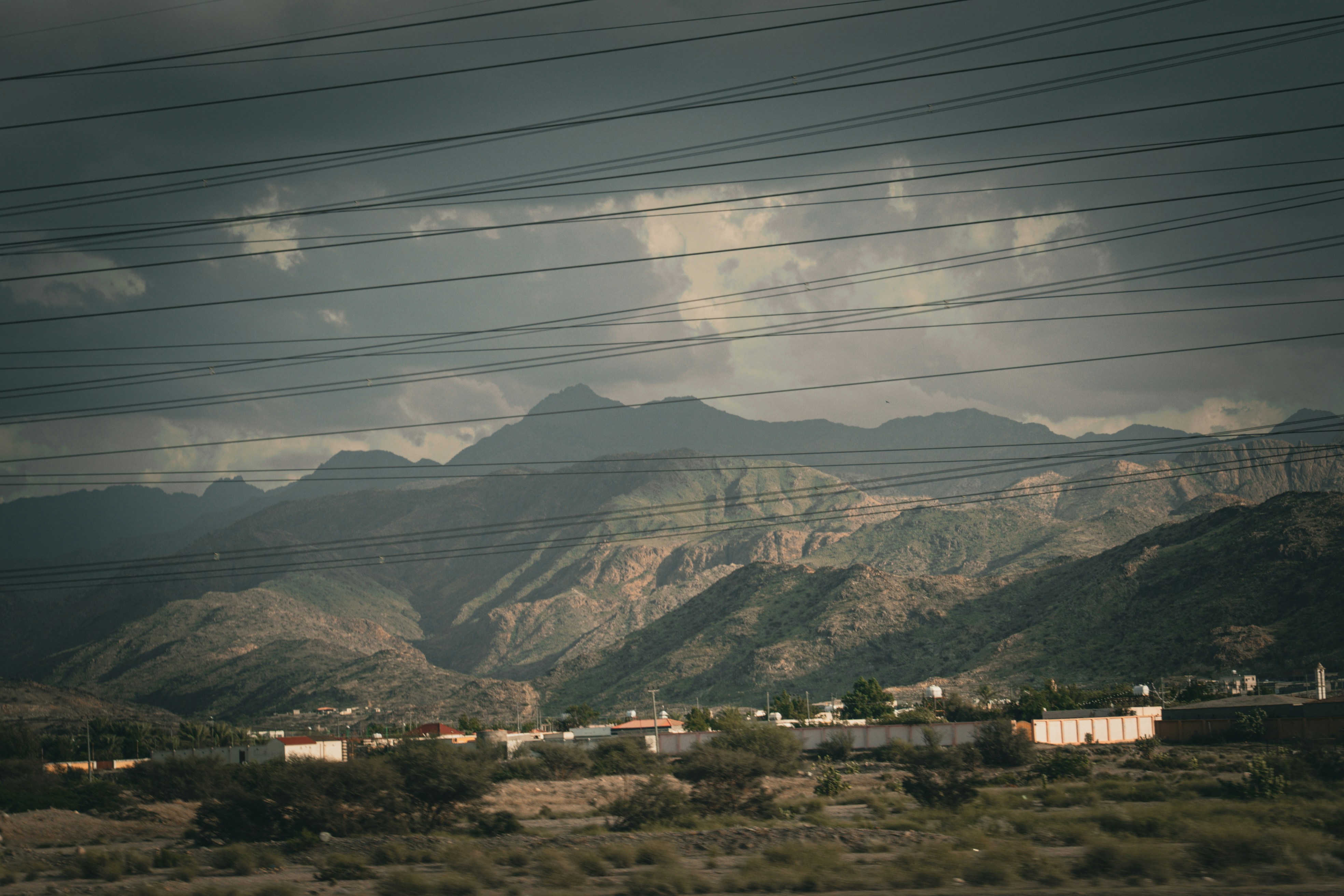 Mountains and power lines under a cloudy sky.