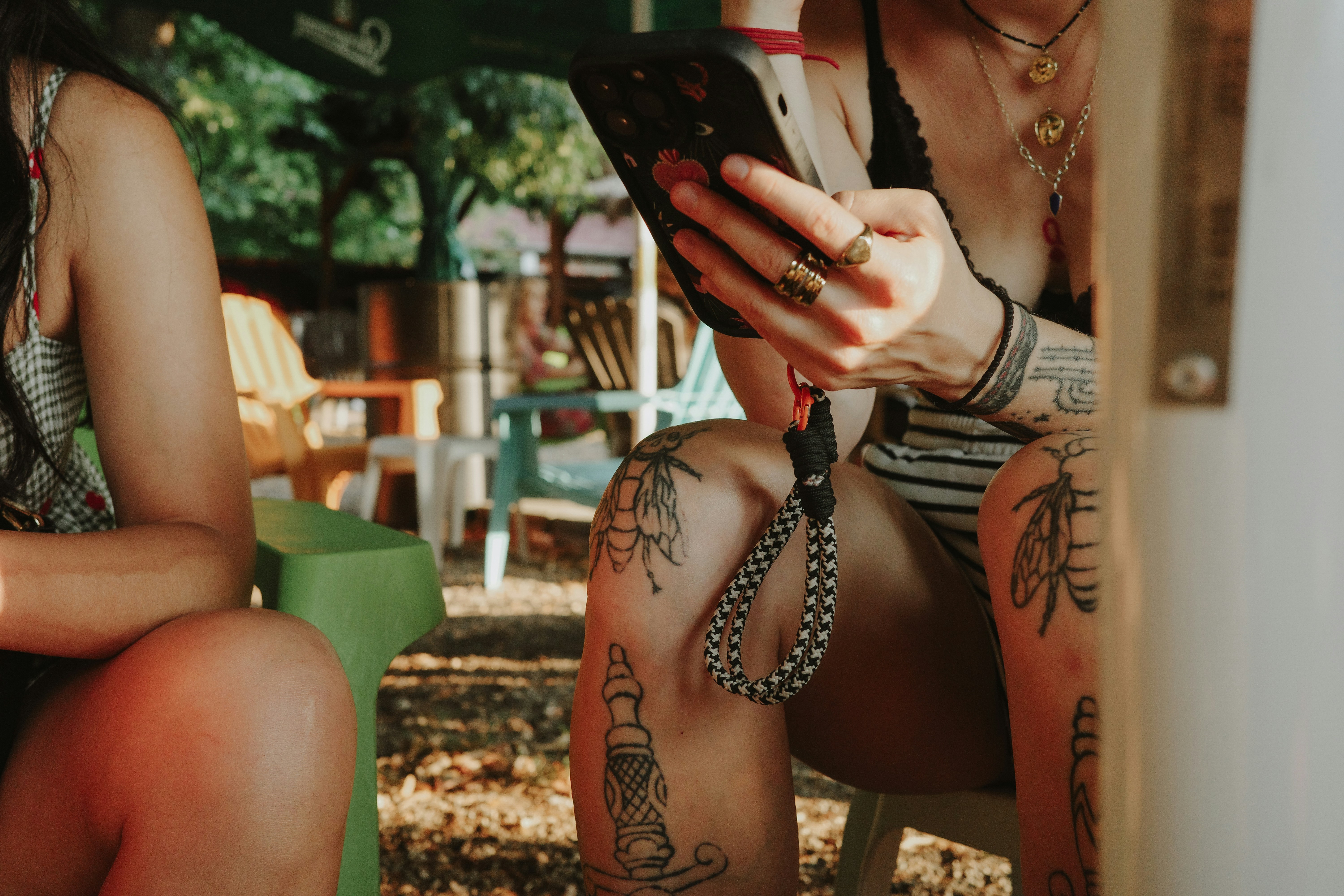 A woman with tattoos uses her phone outdoors.