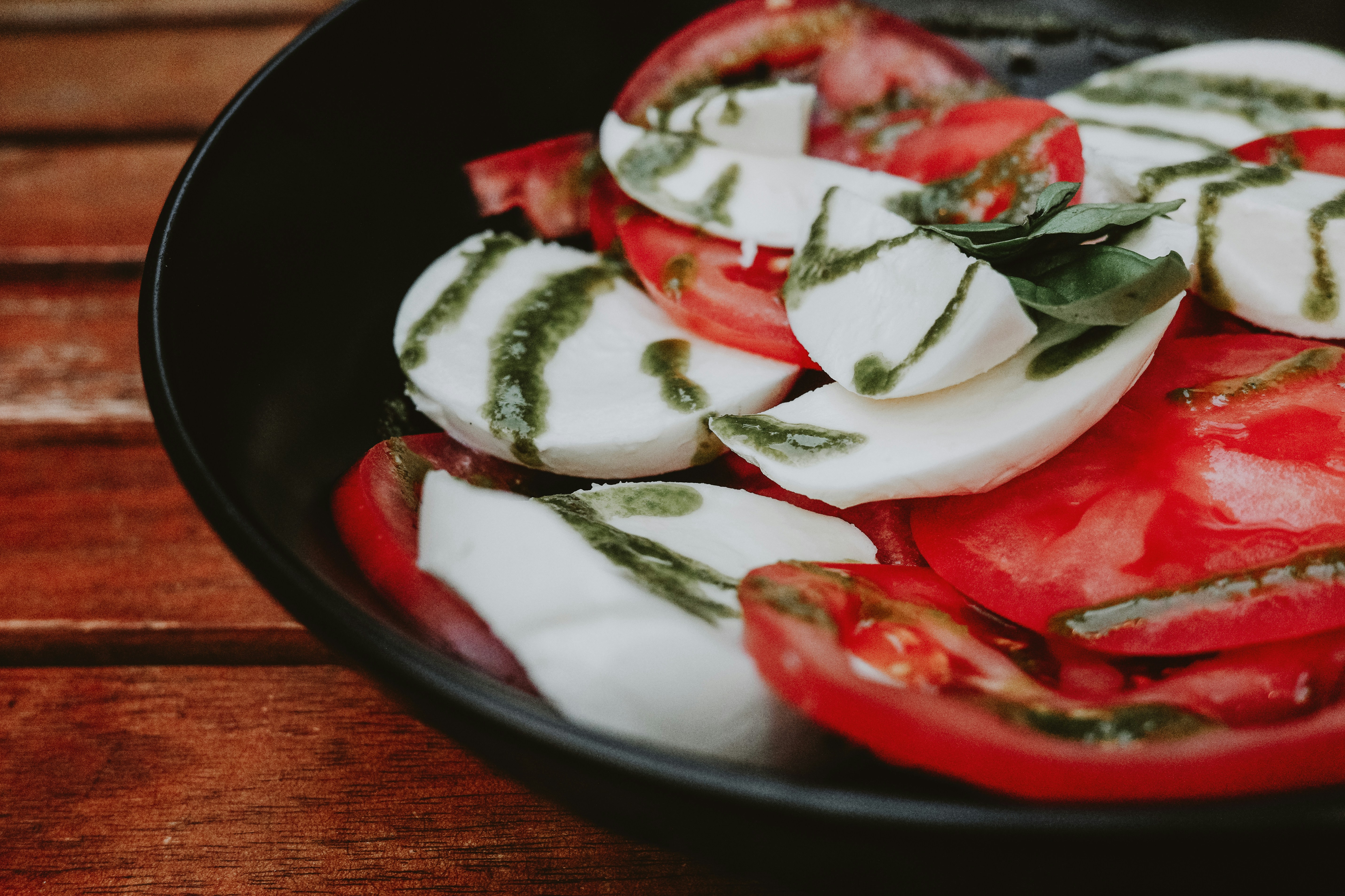 Caprese in Focus: Brushed Basil and Cream in a Black Bowl