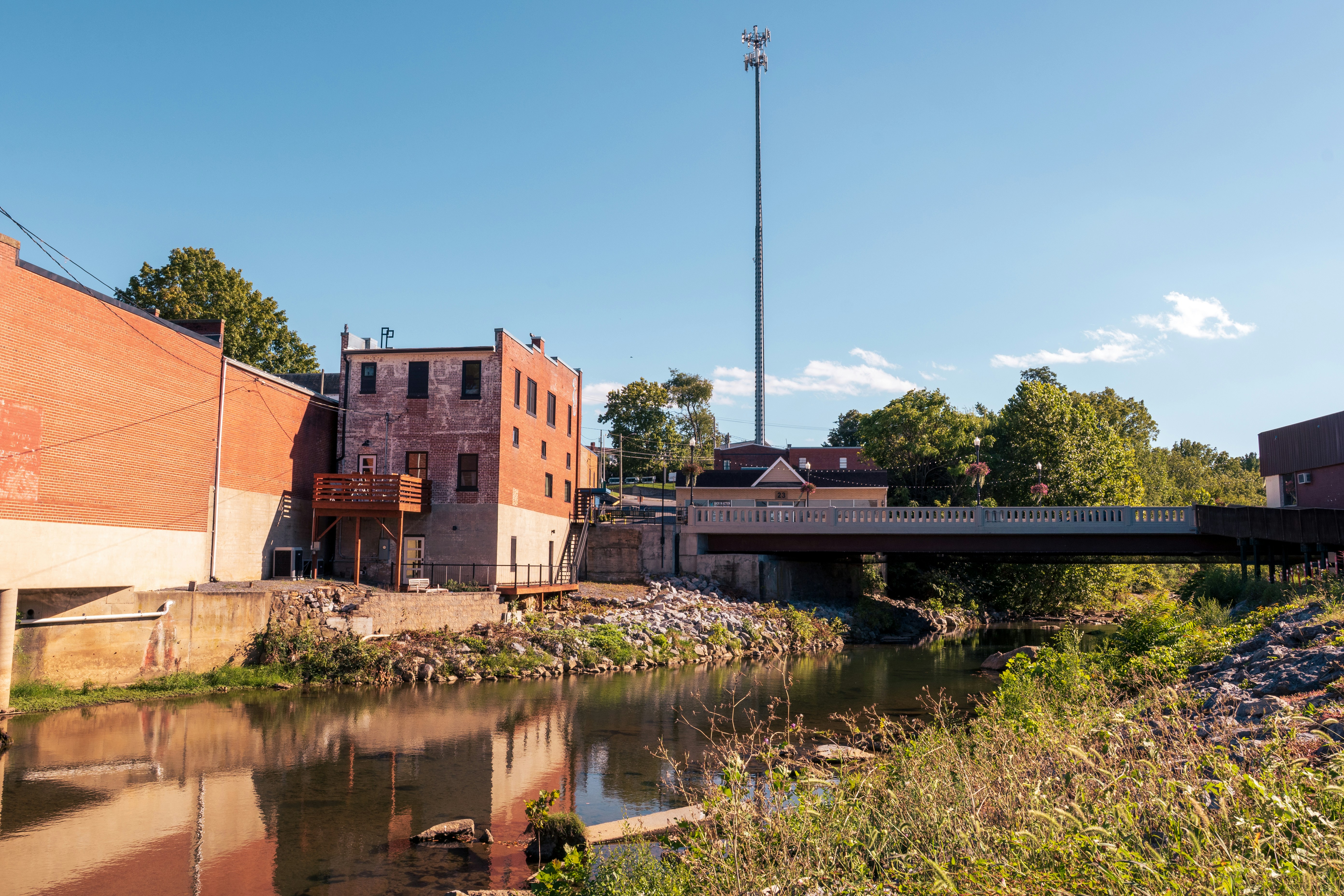 Old buildings sit alongside a calm creek.