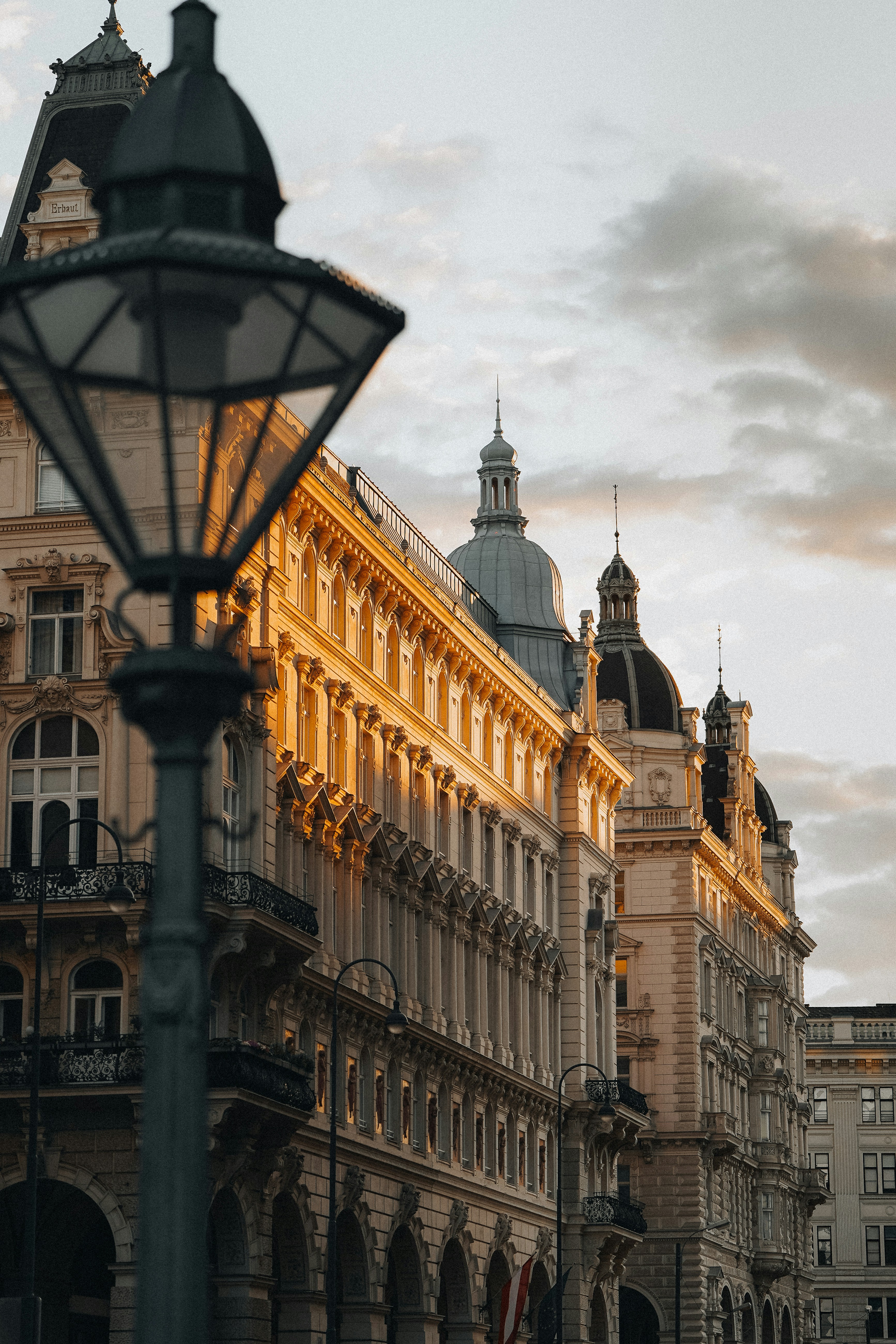 Historic buildings illuminated by the warm glow of sunset, framed by a vintage street lamp. 
