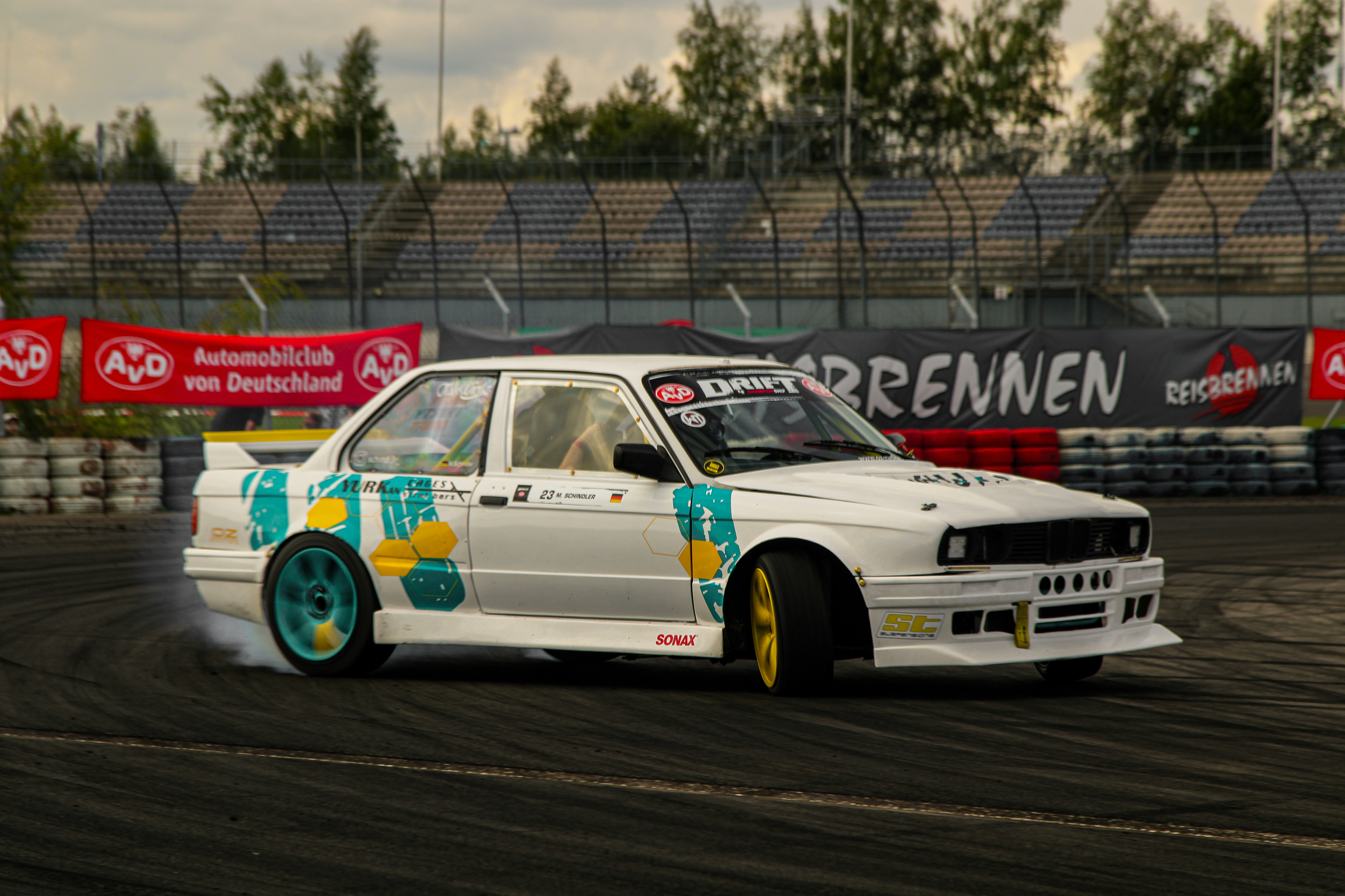 A modified BMW E30 drift car captured in action on a race track. This classic German chassis has been transformed into a purpose-built drift machine, featuring aggressive styling, racing livery, and performance modifications. The E30's perfect balance and rear-wheel-drive layout make it a favorite among drift enthusiasts and professional drivers. Perfect for motorsport content, drifting culture, or automotive racing photography. | A drift car slides around a race track.