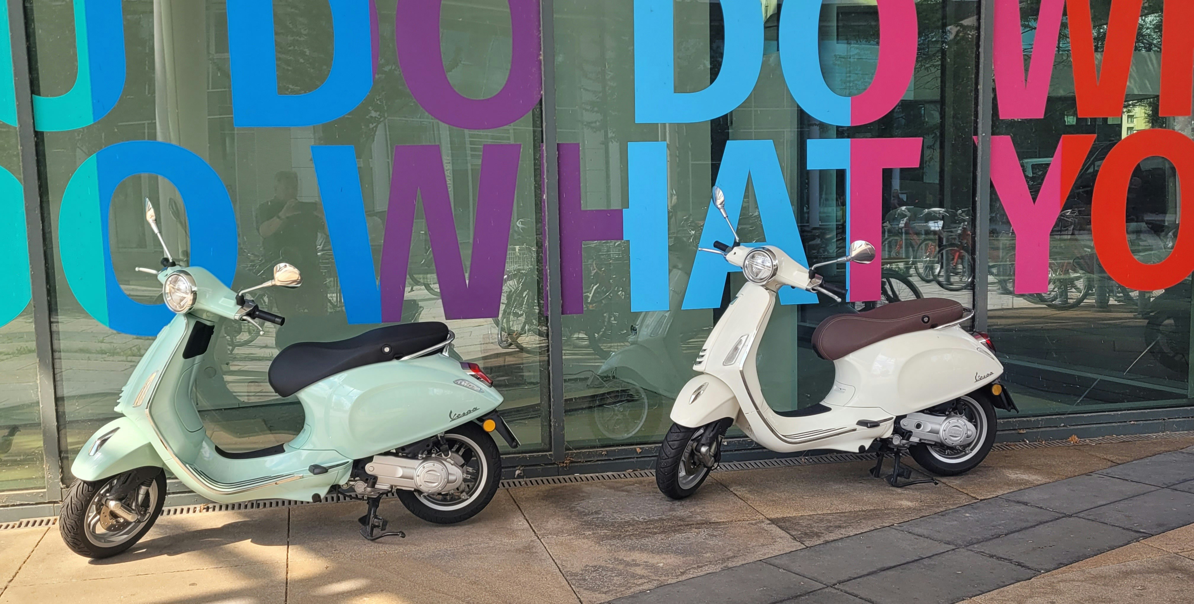 Two scooters are parked in front of colorful letters.