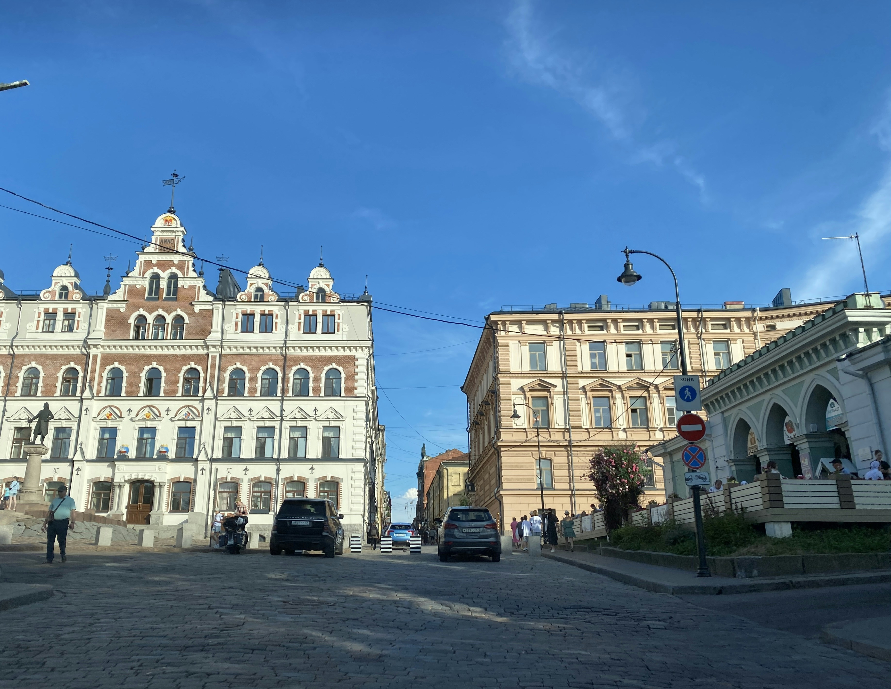 Historic buildings line a cobblestone street, showcasing architectural diversity under a clear blue sky.