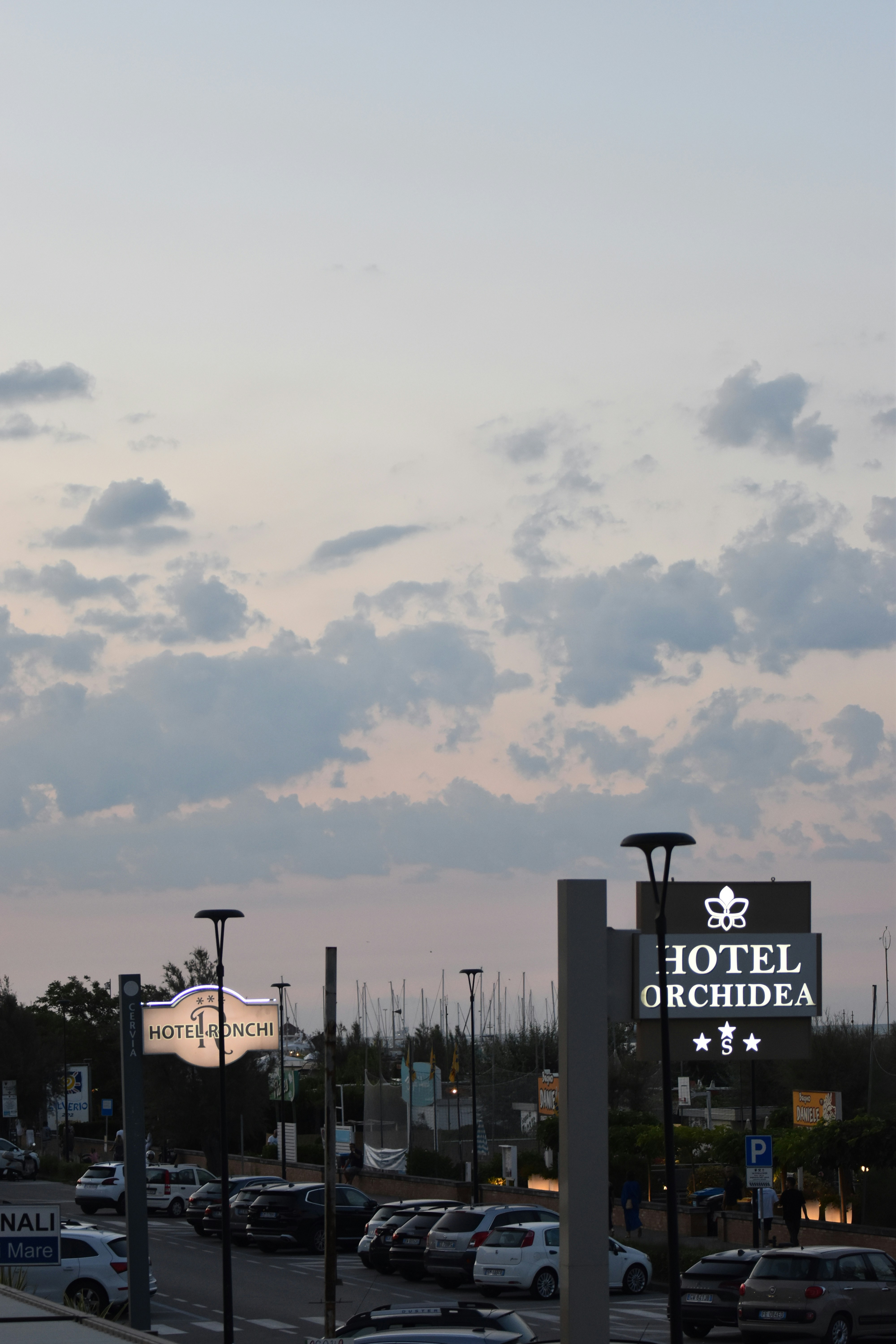 Hotel signs stand below a cloudy sky.