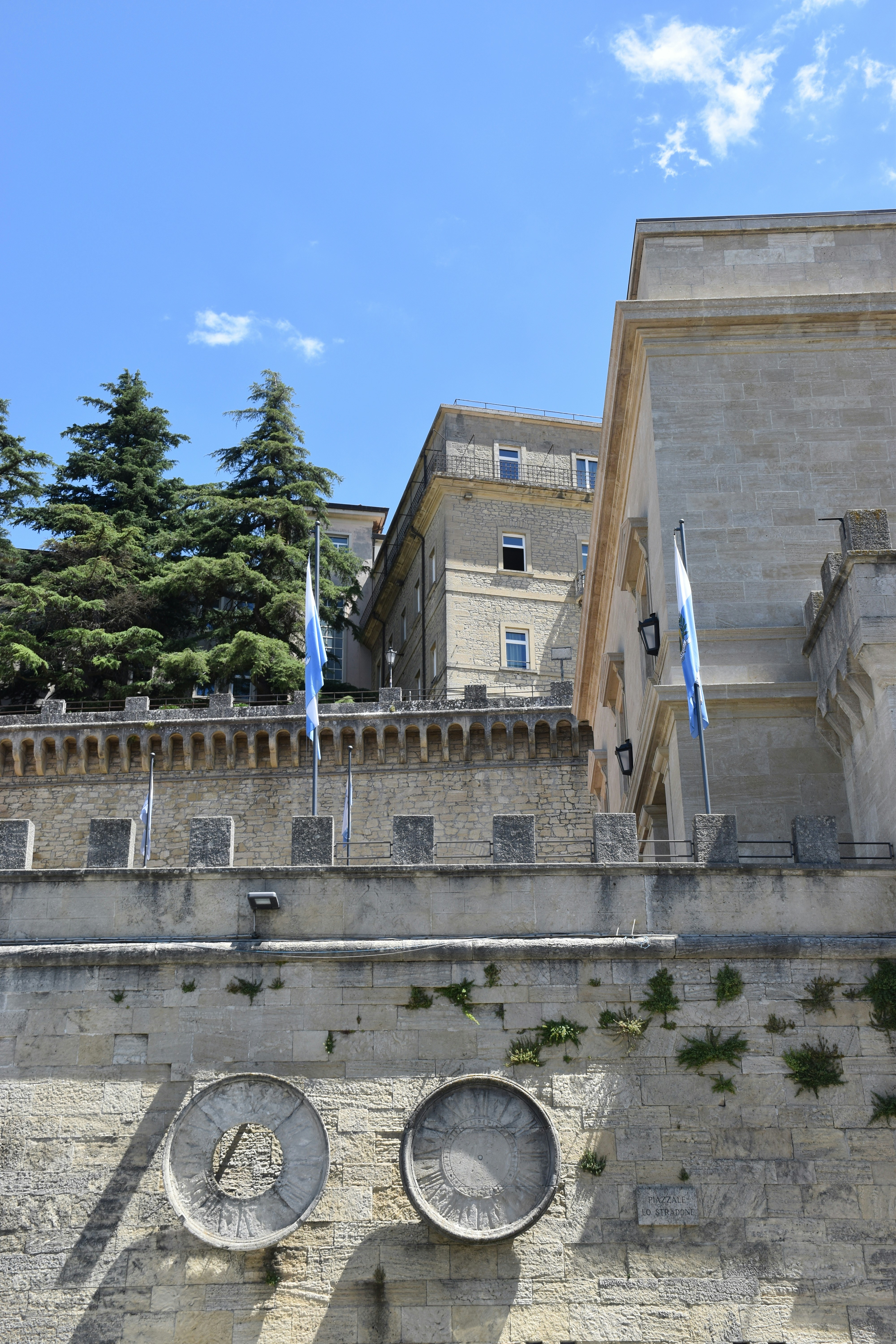 Blue banners flutter along a sunlit fortress façade