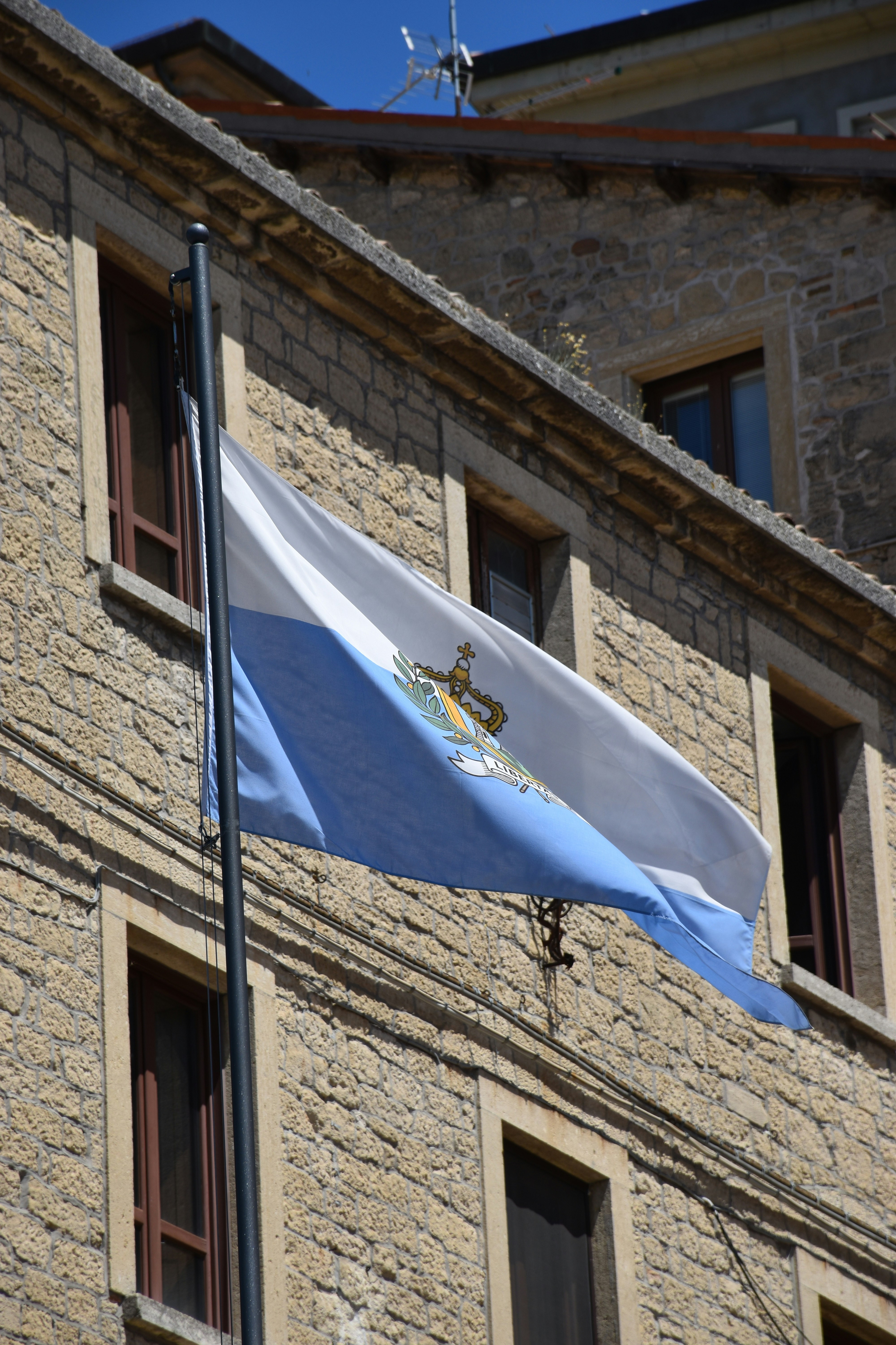 A san marino flag waves in front of a building.
